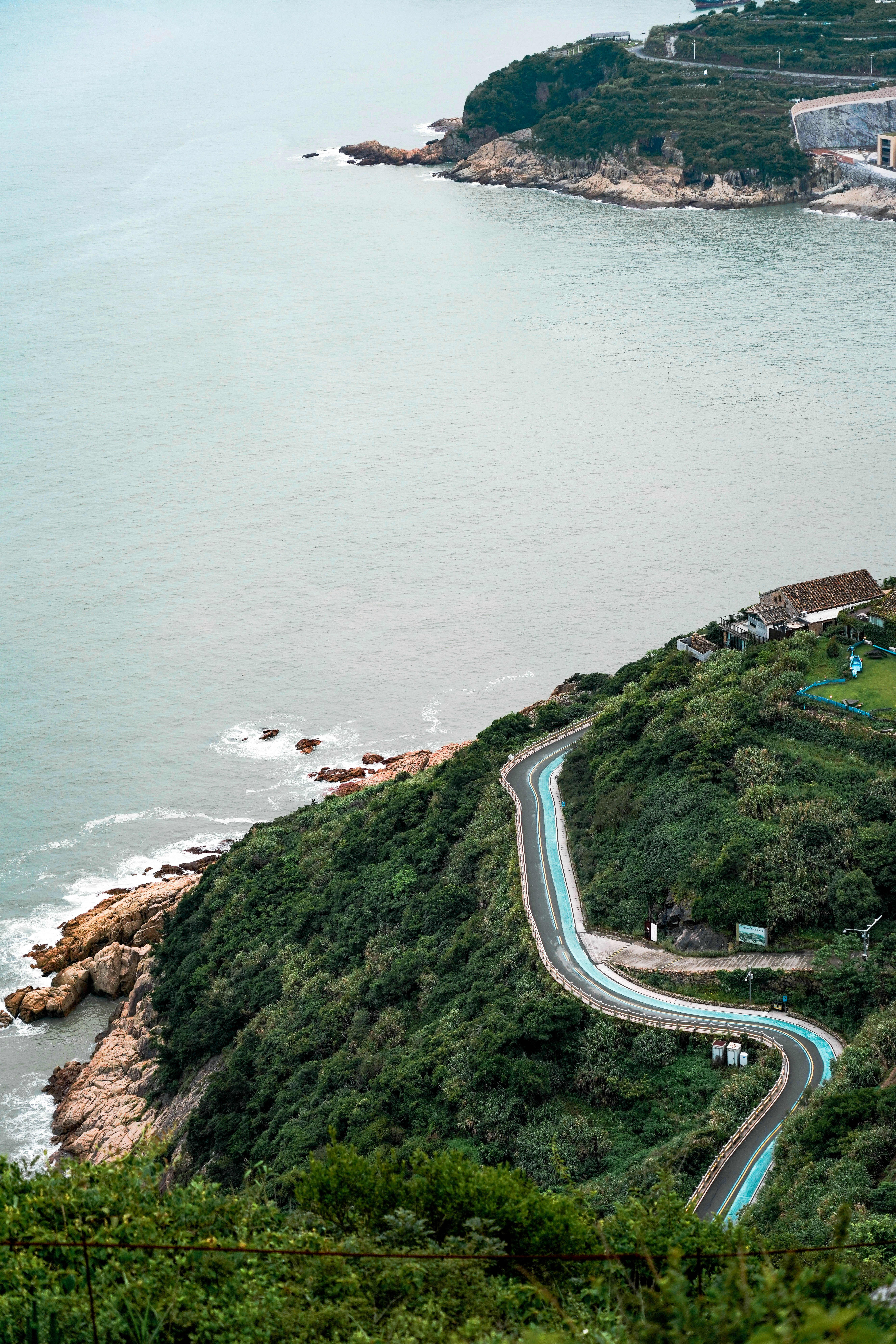 A winding road on the side of a hill next to the ocean