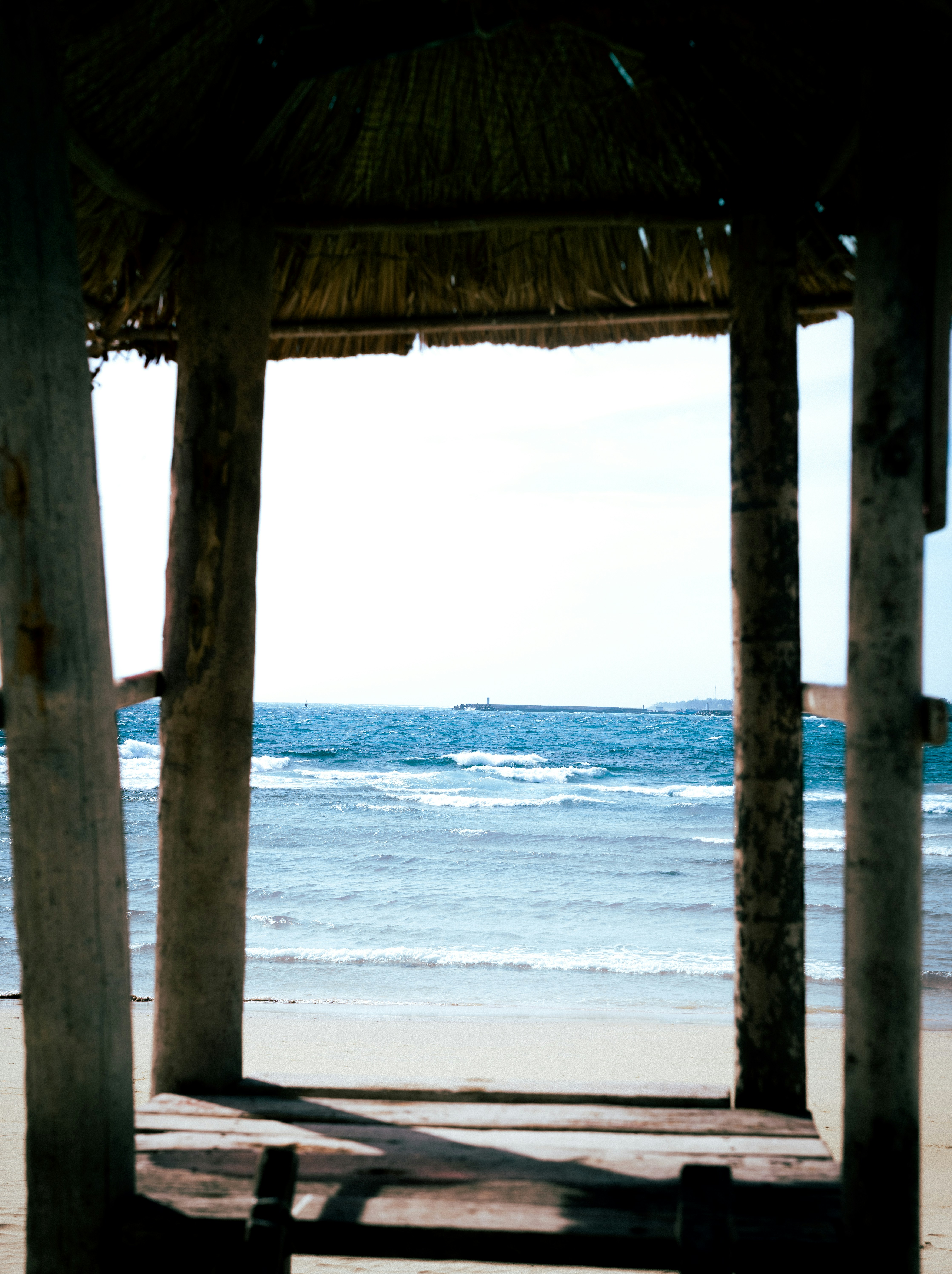 A gazebo sitting on top of a sandy beach next to the ocean
