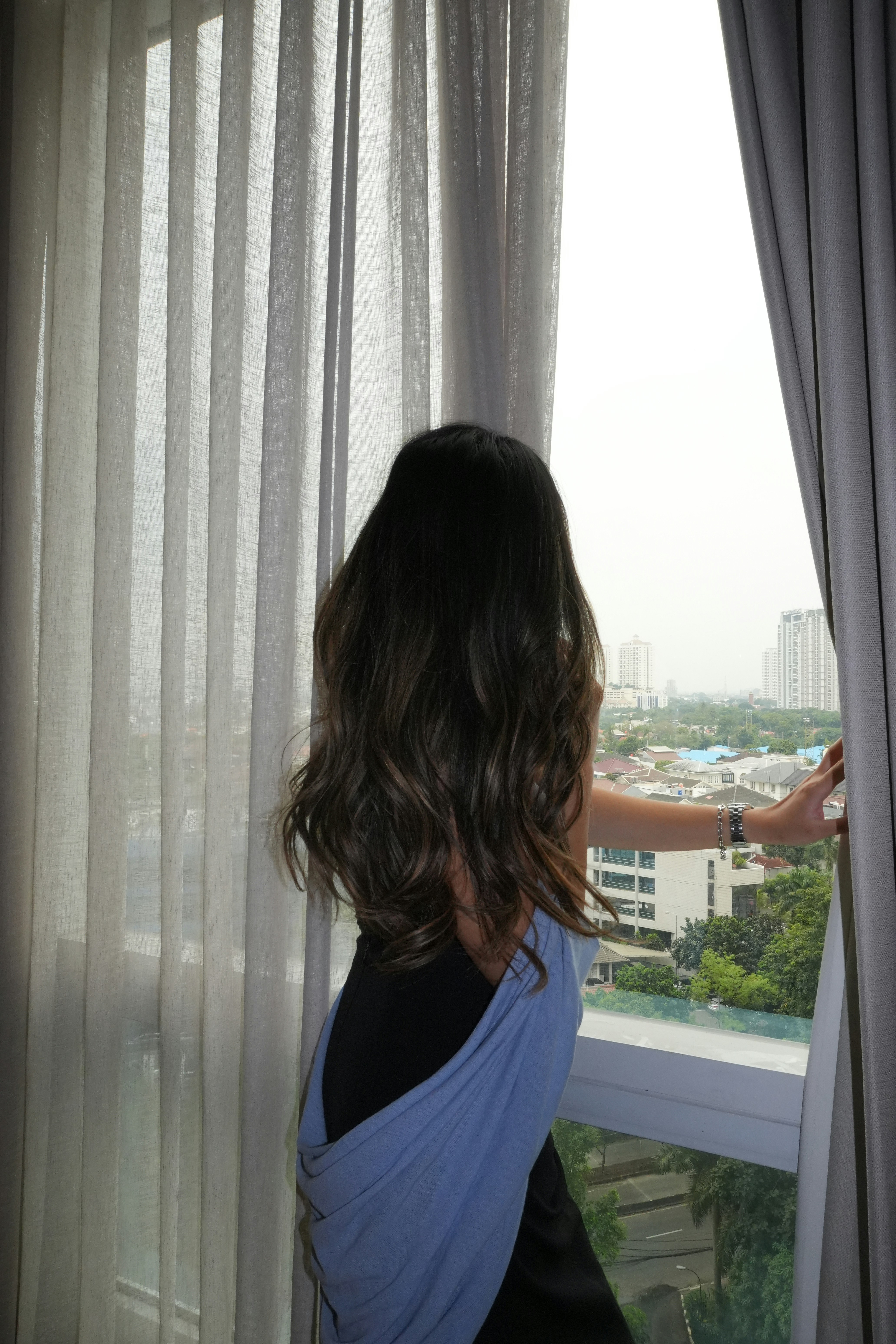 A woman looking out a window at the city photo – Free City Image on ...