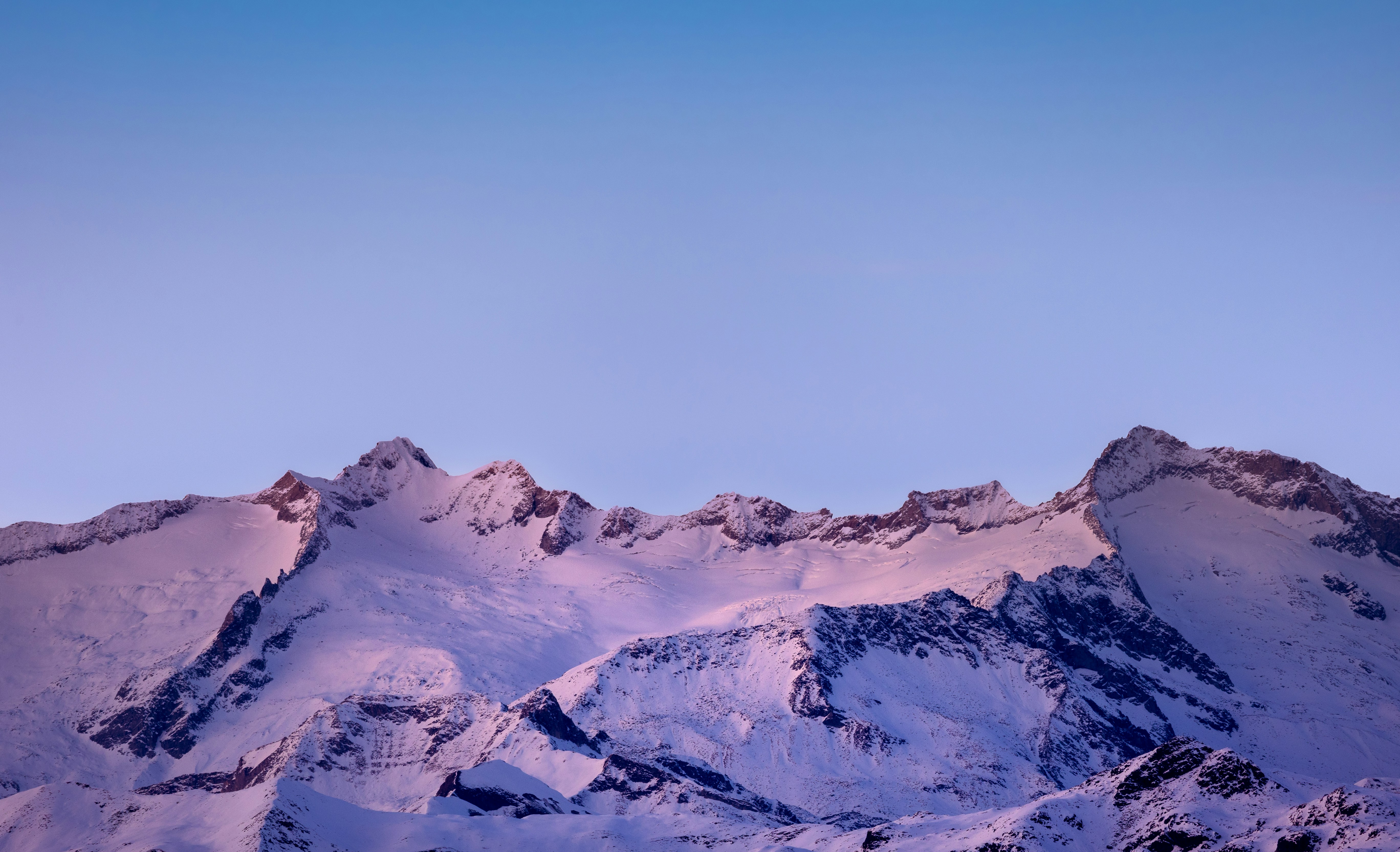 A snow covered mountain range under a blue sky photo – Free Nature ...