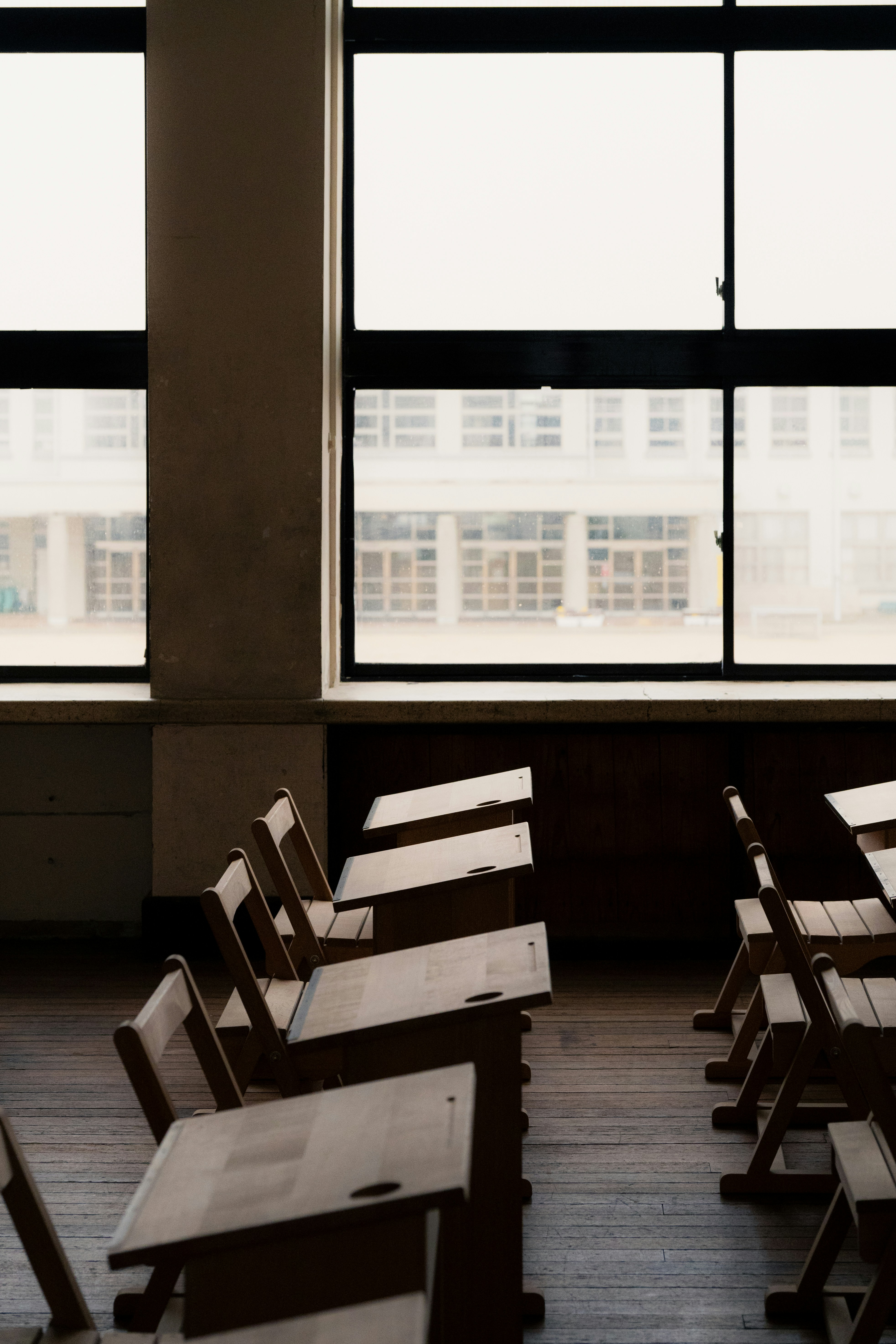 A row of wooden desks in front of large windows photo – Free School ...