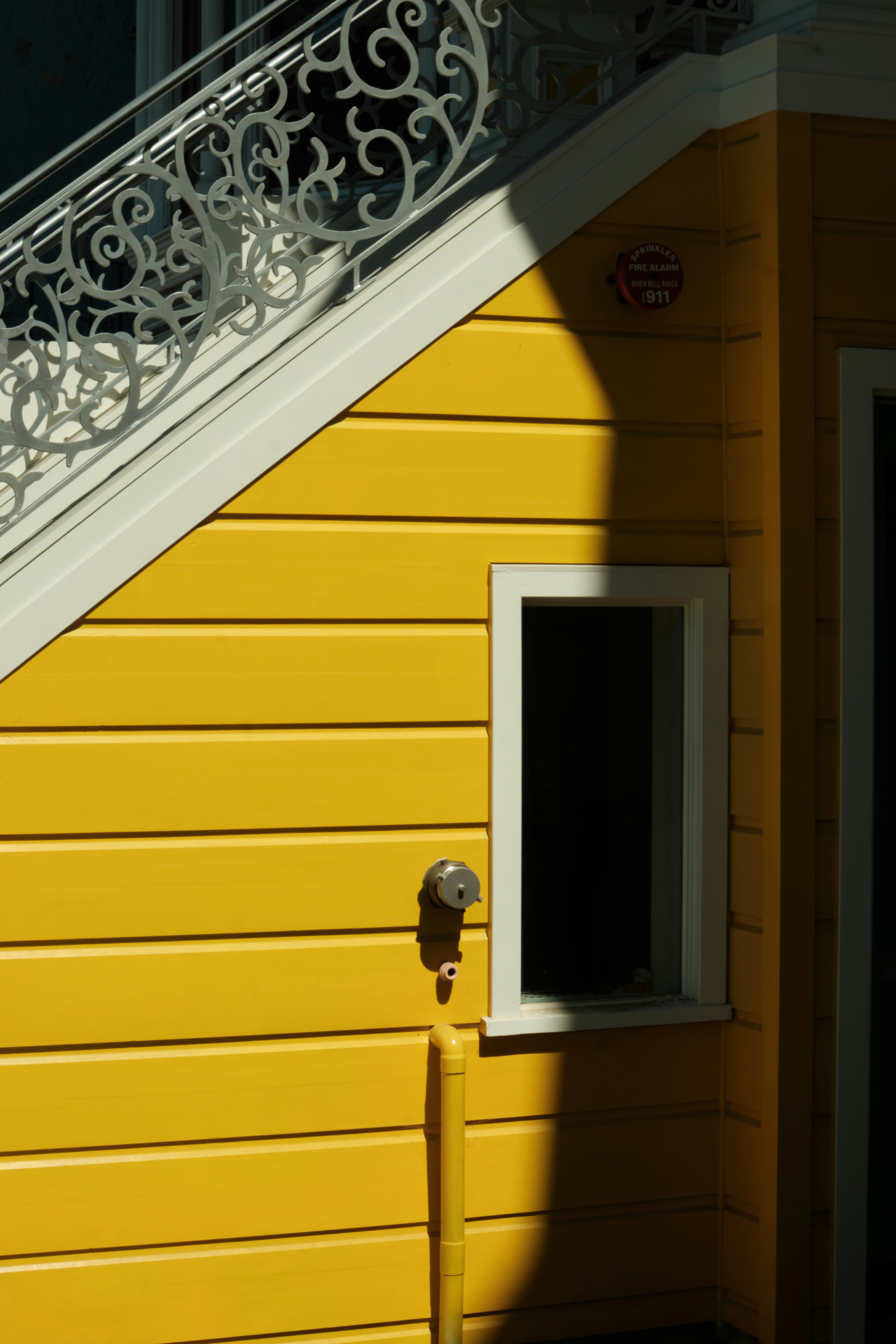 Sunlit Yellow Facade Framed by Ornate Staircase Shadow