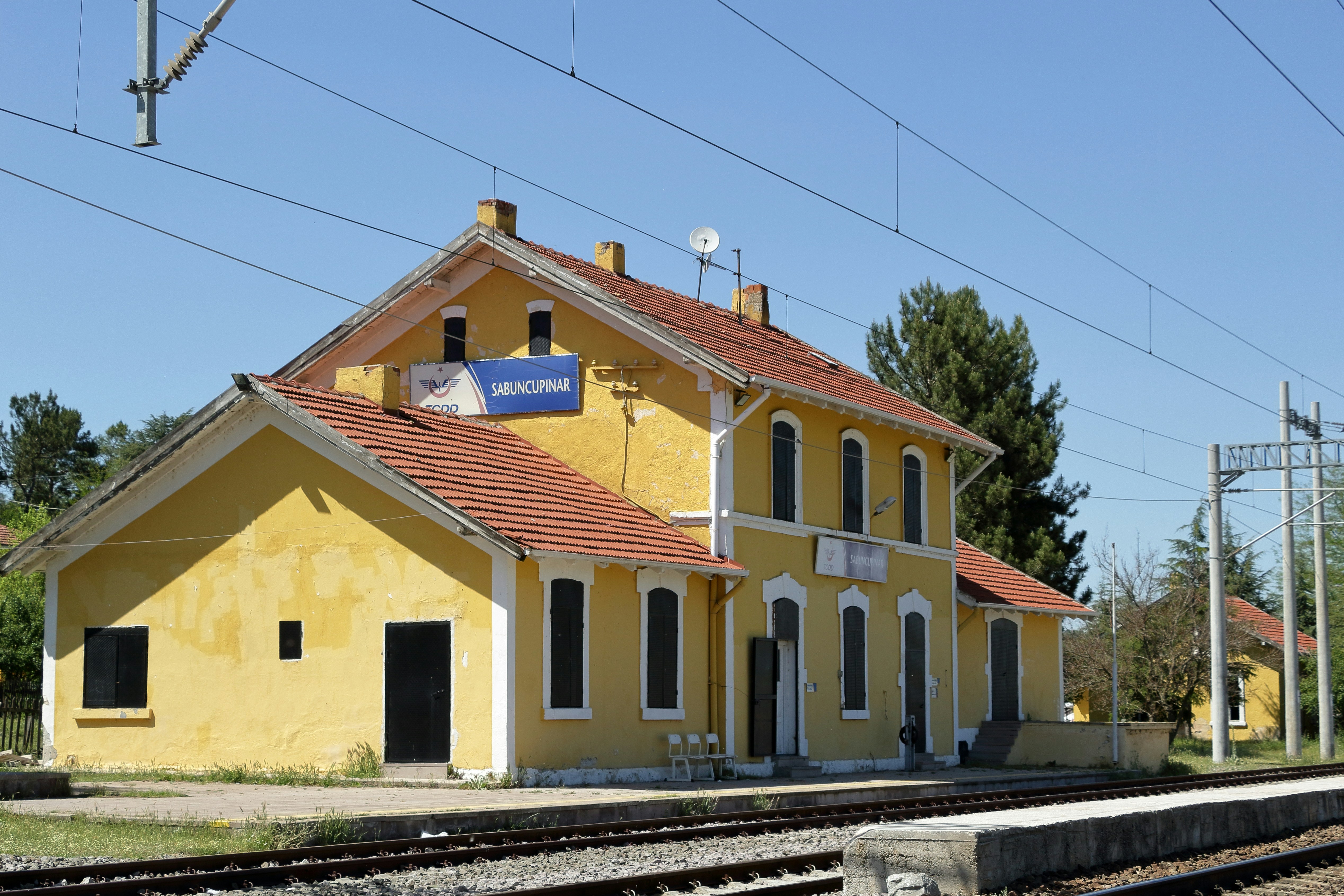 A yellow train station with a train on the tracks photo – Free House ...