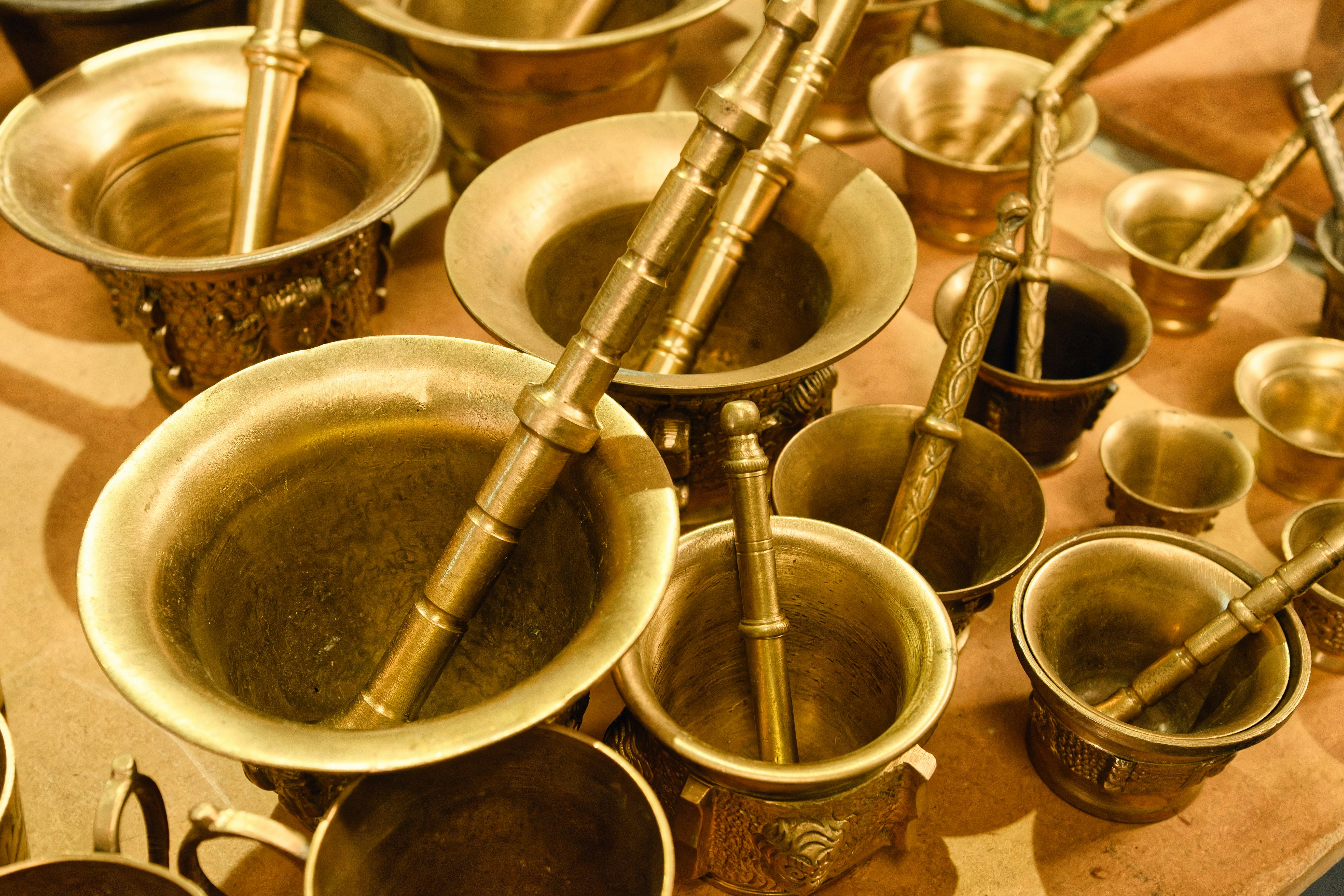 Collection of intricately designed brass mortars and pestles at a vibrant market stall.
