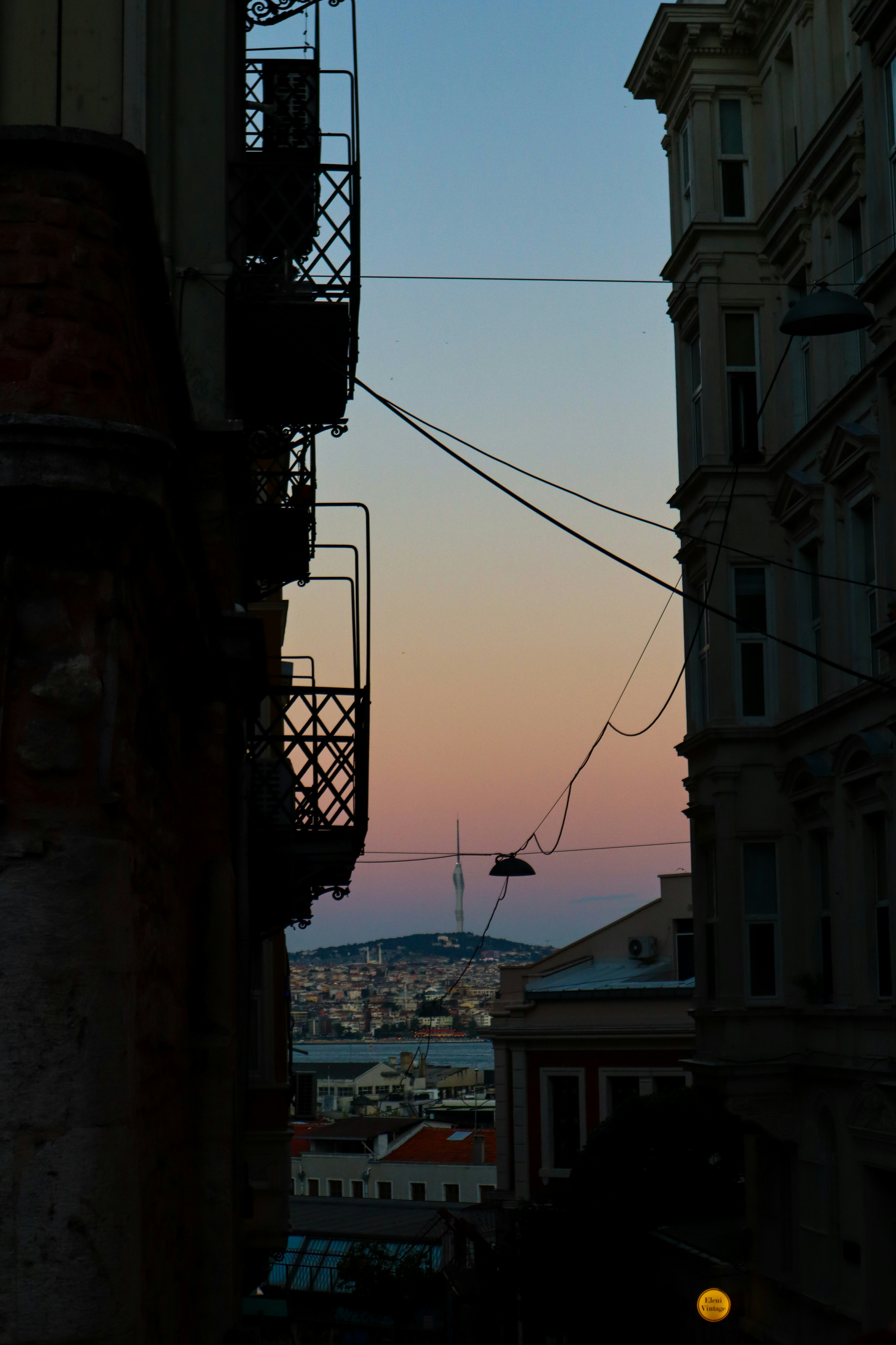 Sunset Between Facades: A Distant Tower Emerges Over a Narrow City Canyon