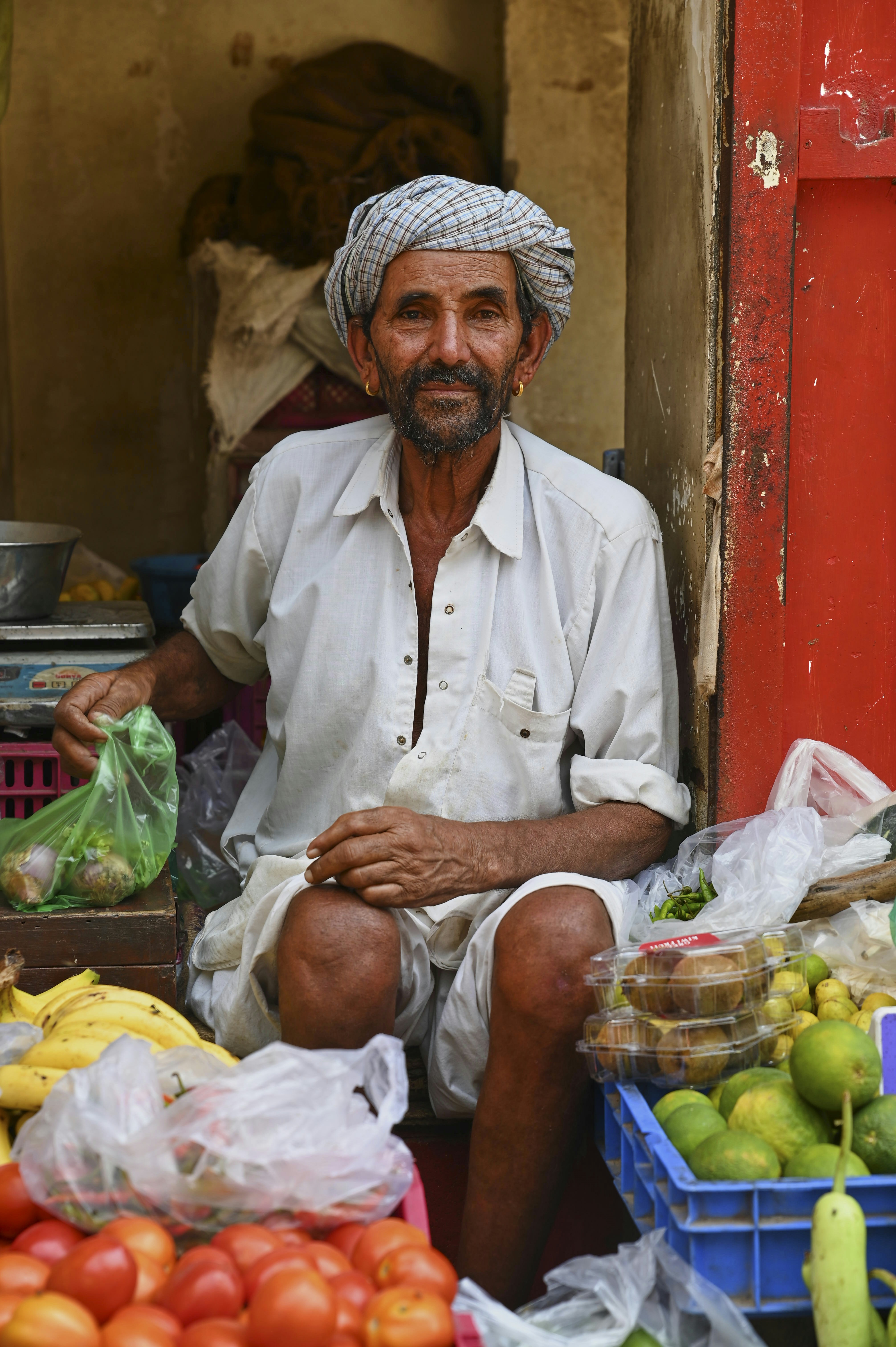 turban man | A man sitting in front of a fruit stand