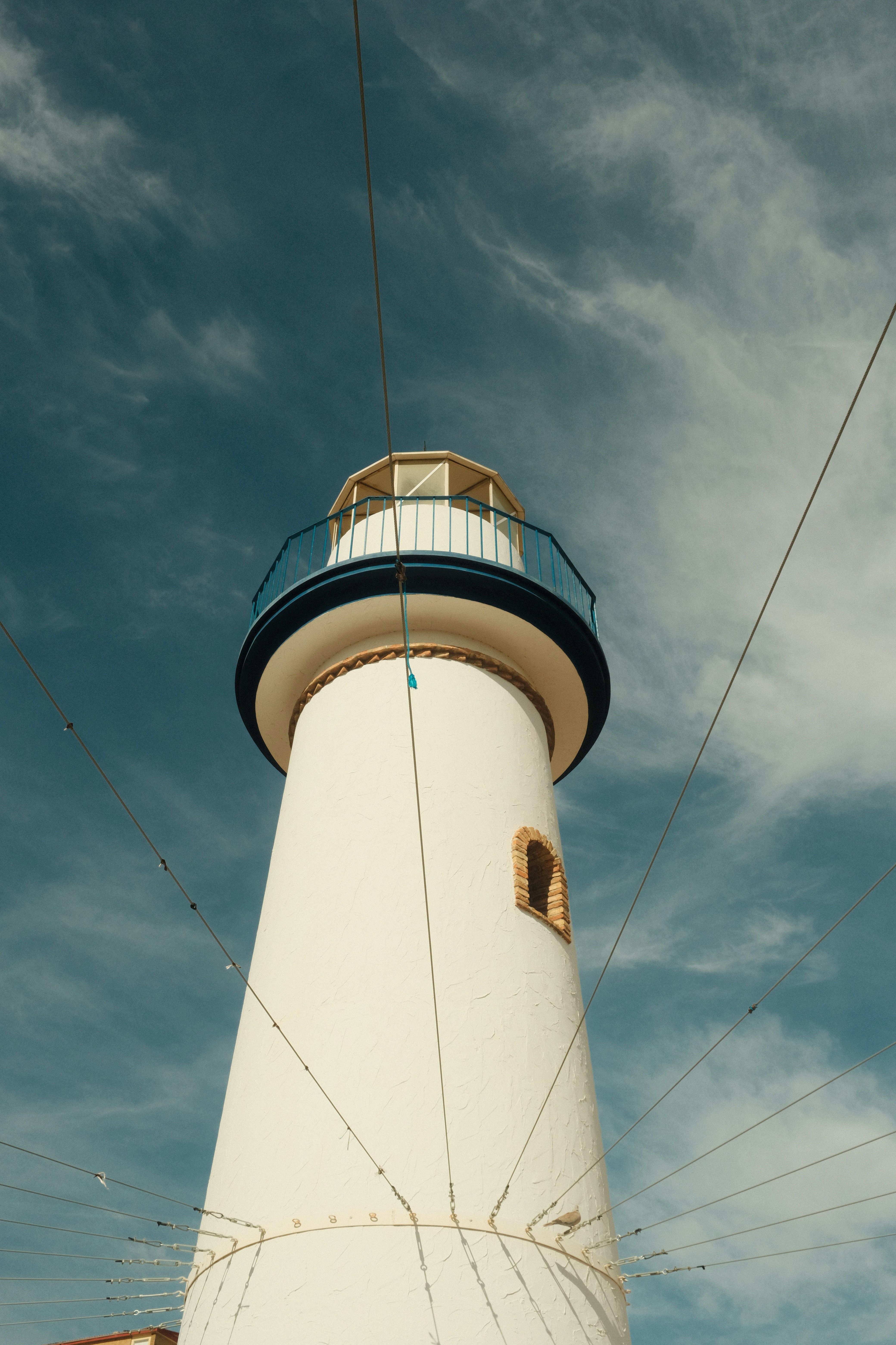 Beacon in the Blue: A Coastal Lighthouse Framed by Taut Cables