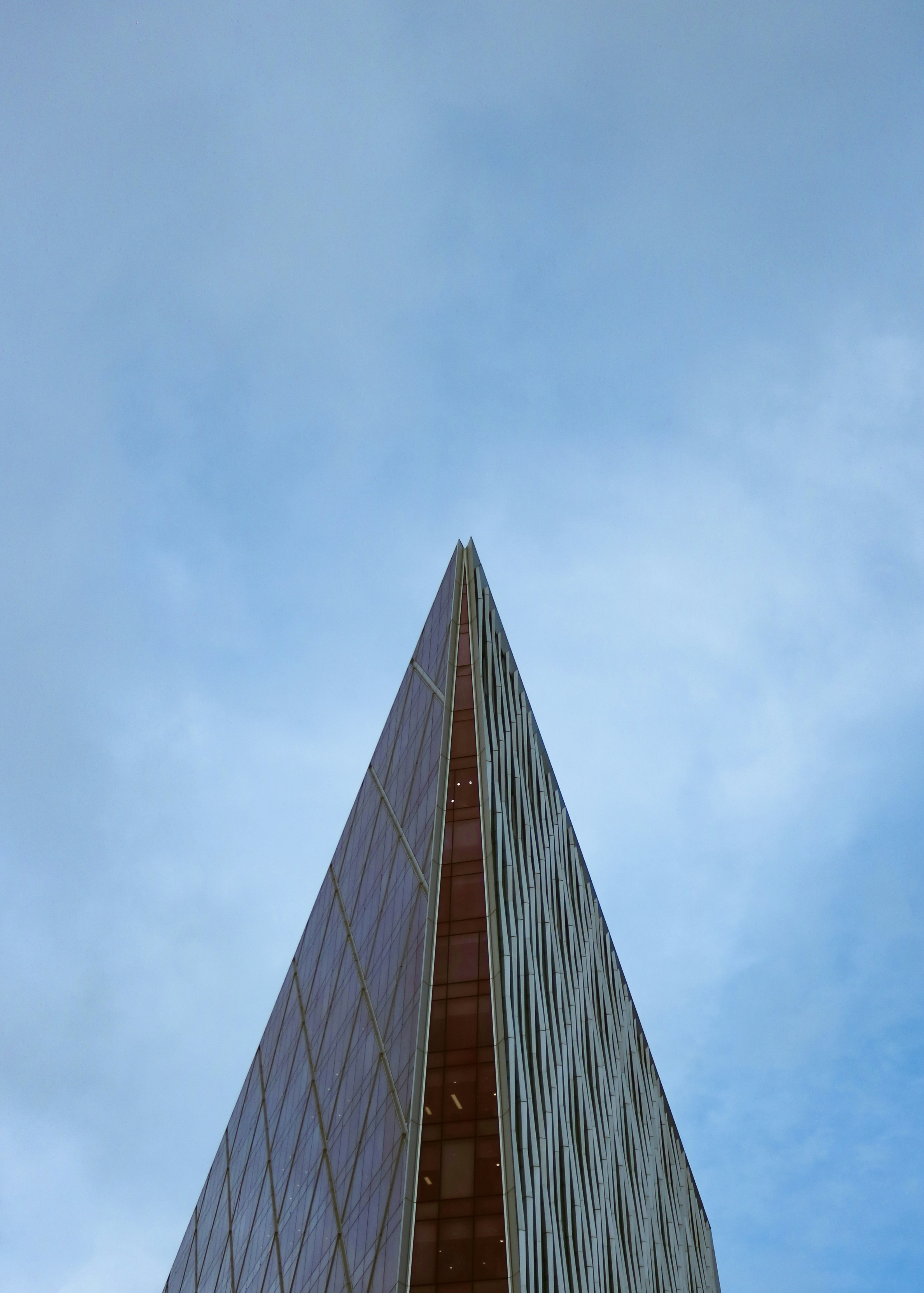 Red Sharp angular building cutting the blue sky, all in glass and metal