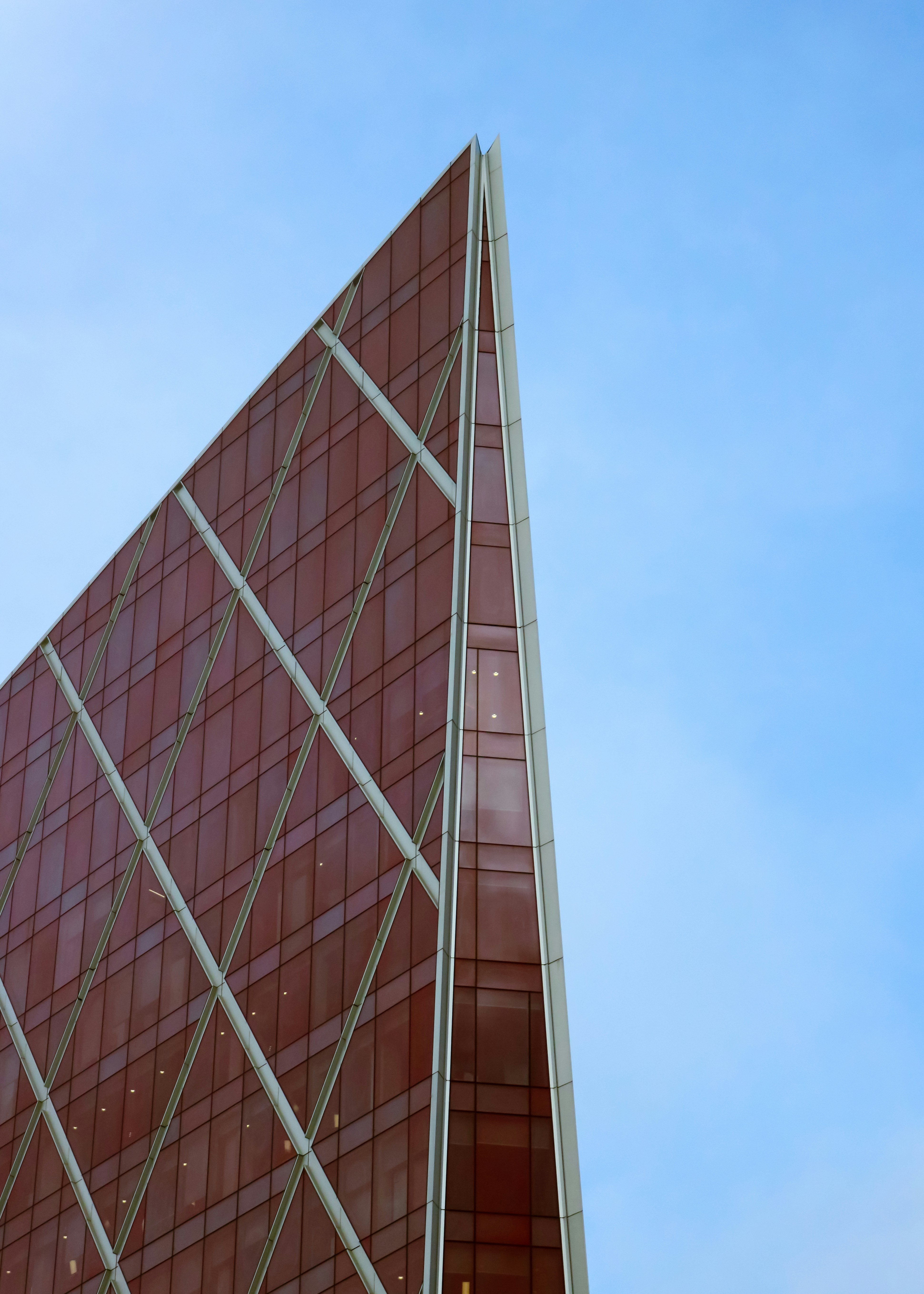 Red Sharp angular building cutting the blue sky, all in glass and metal