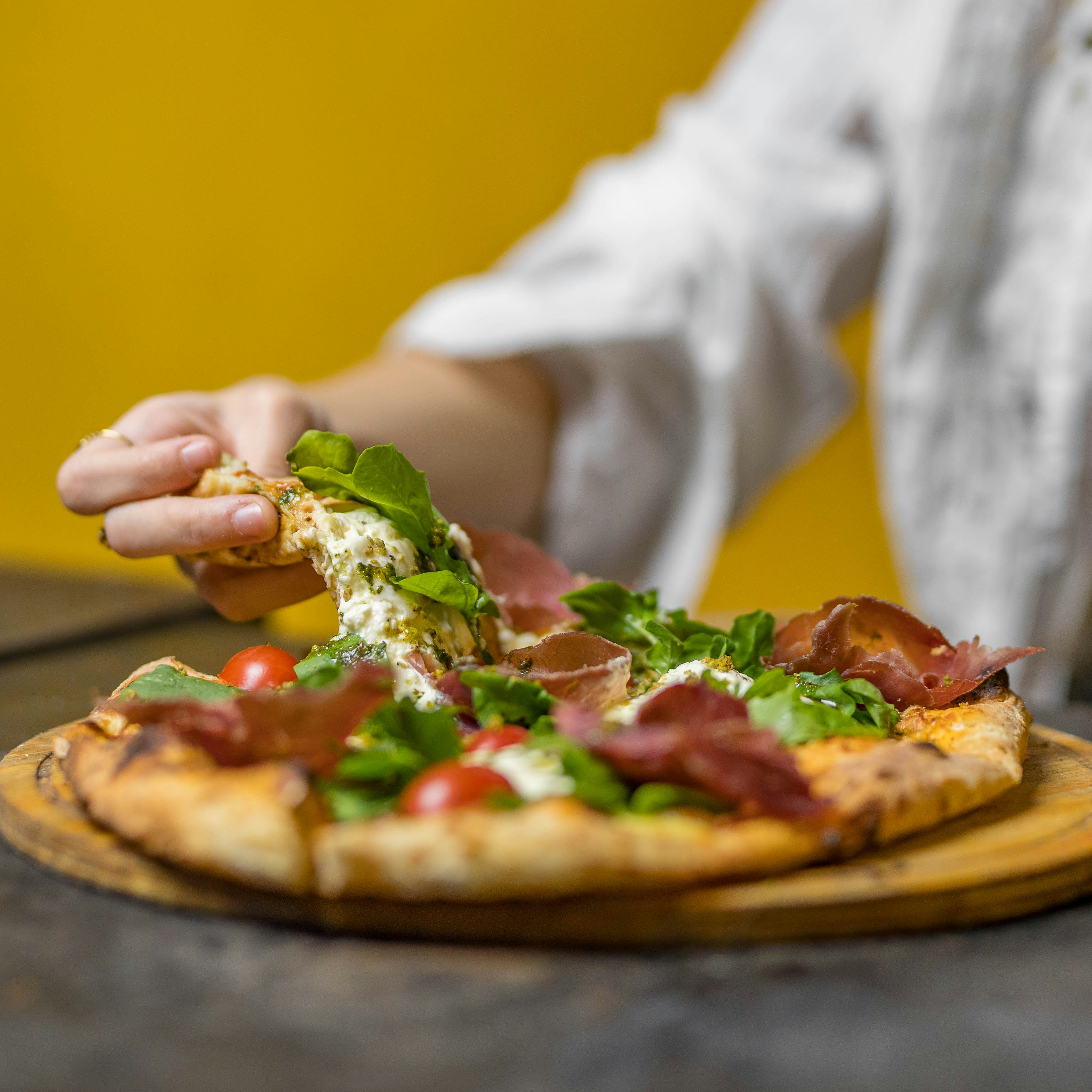 A person grabbing a piece of food from a pizza photo – Free Food Image ...
