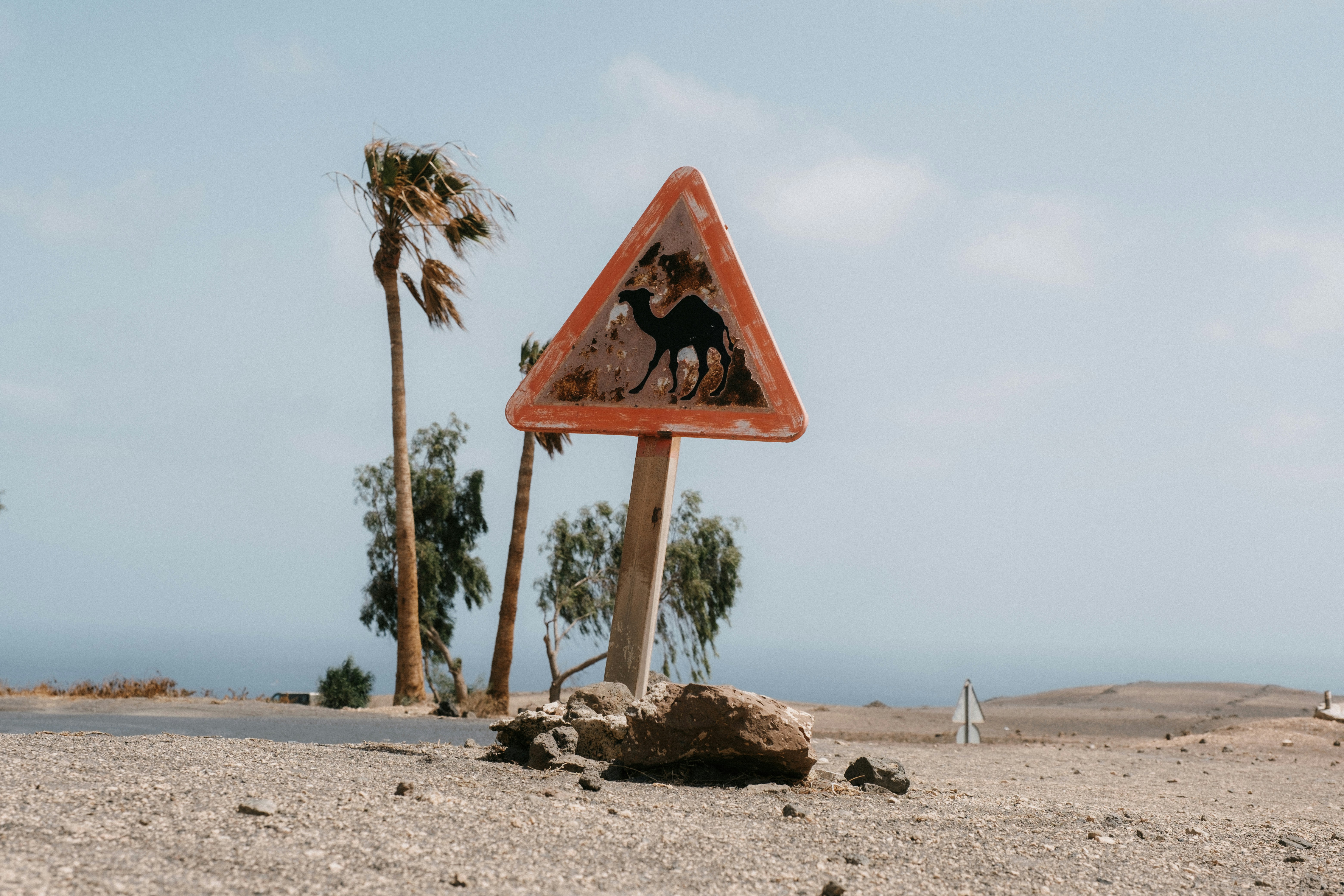 A triangle shaped sign sitting on top of a sandy beach photo – Free ...