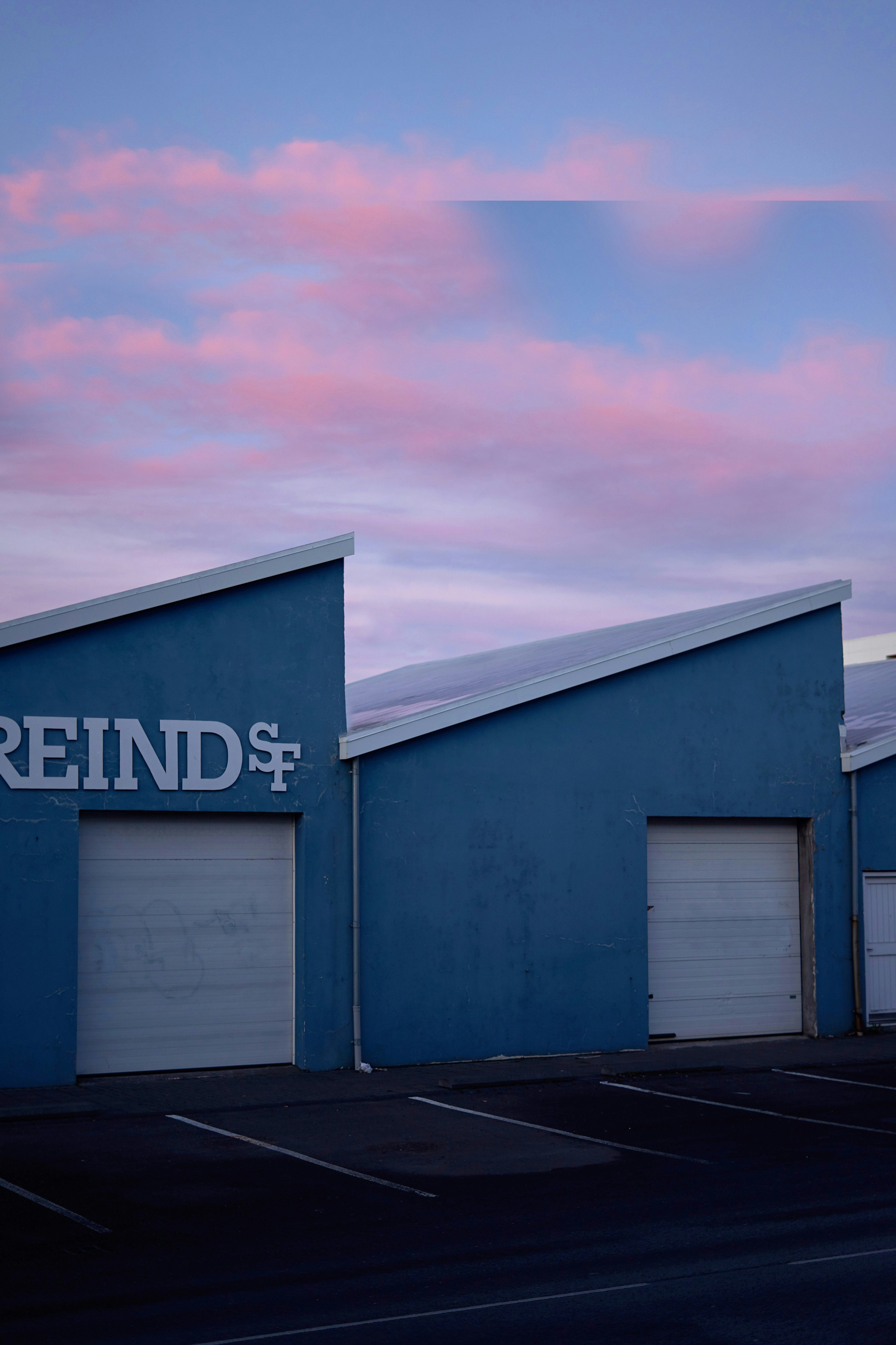 Blue Warehouses at Dusk: Quiet Geometry Under a Luminous Pink Sky