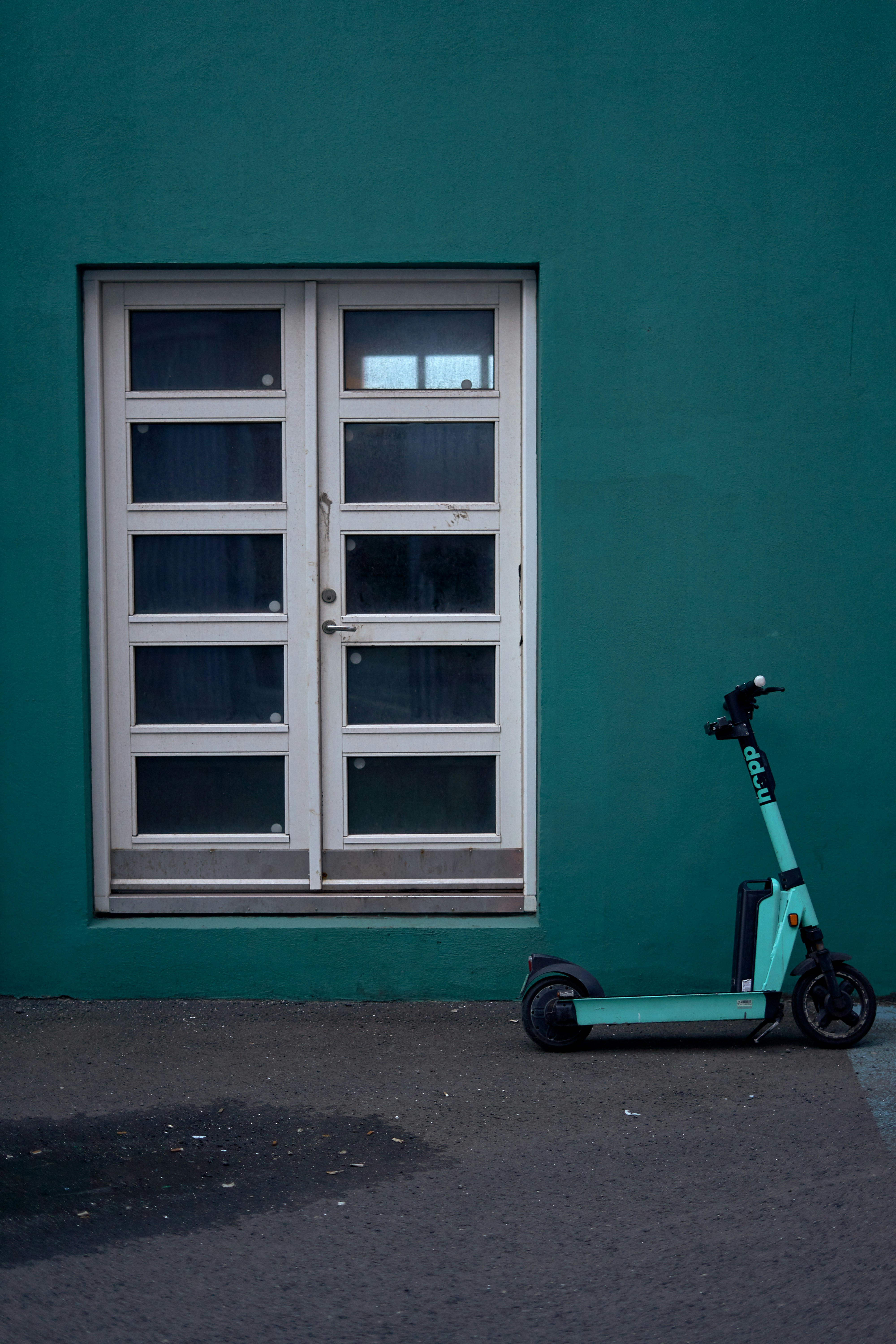 Teal Facade with Paneled Door and a Resting E-Scooter