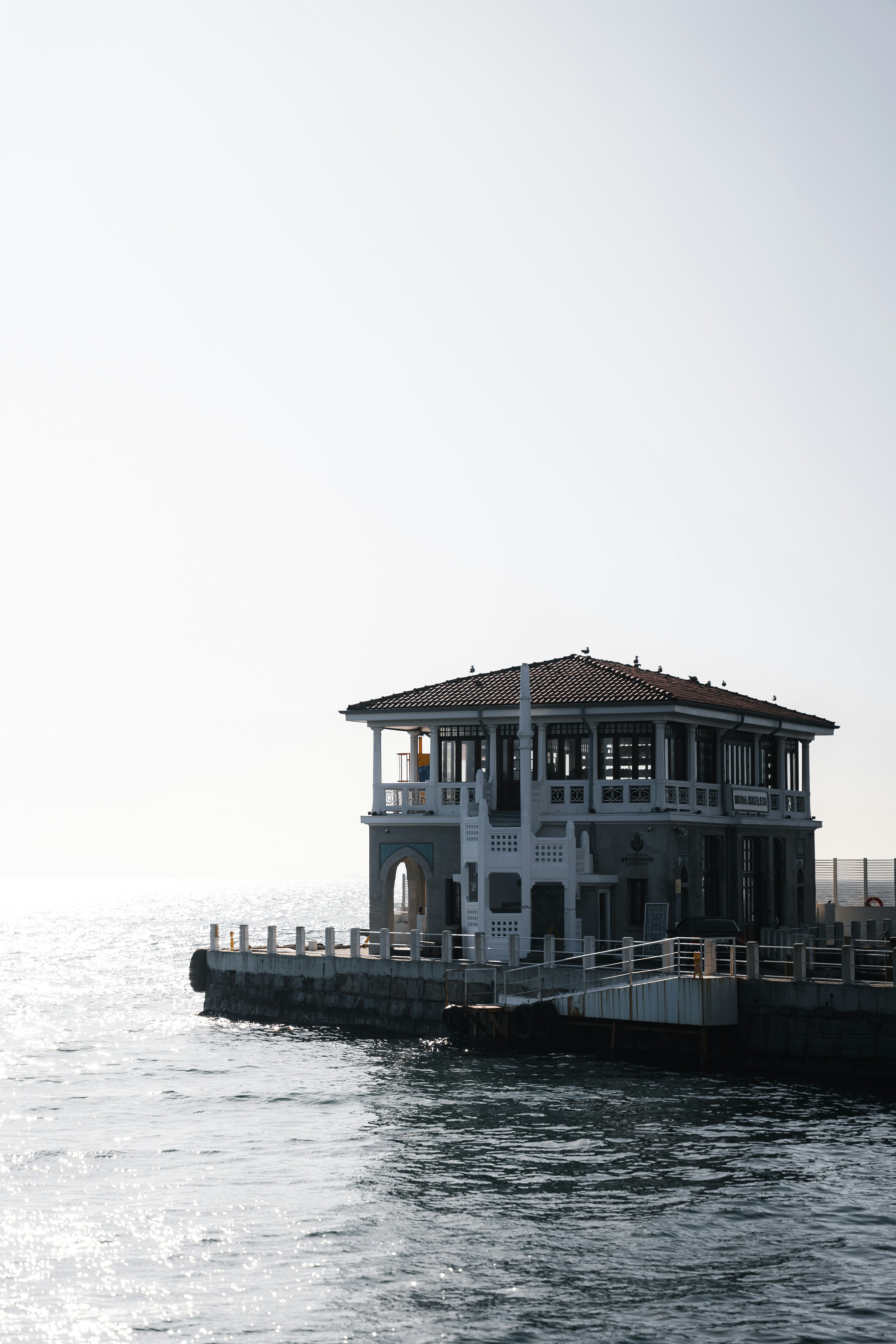 A house sitting on top of a pier next to the ocean photo – Free ...