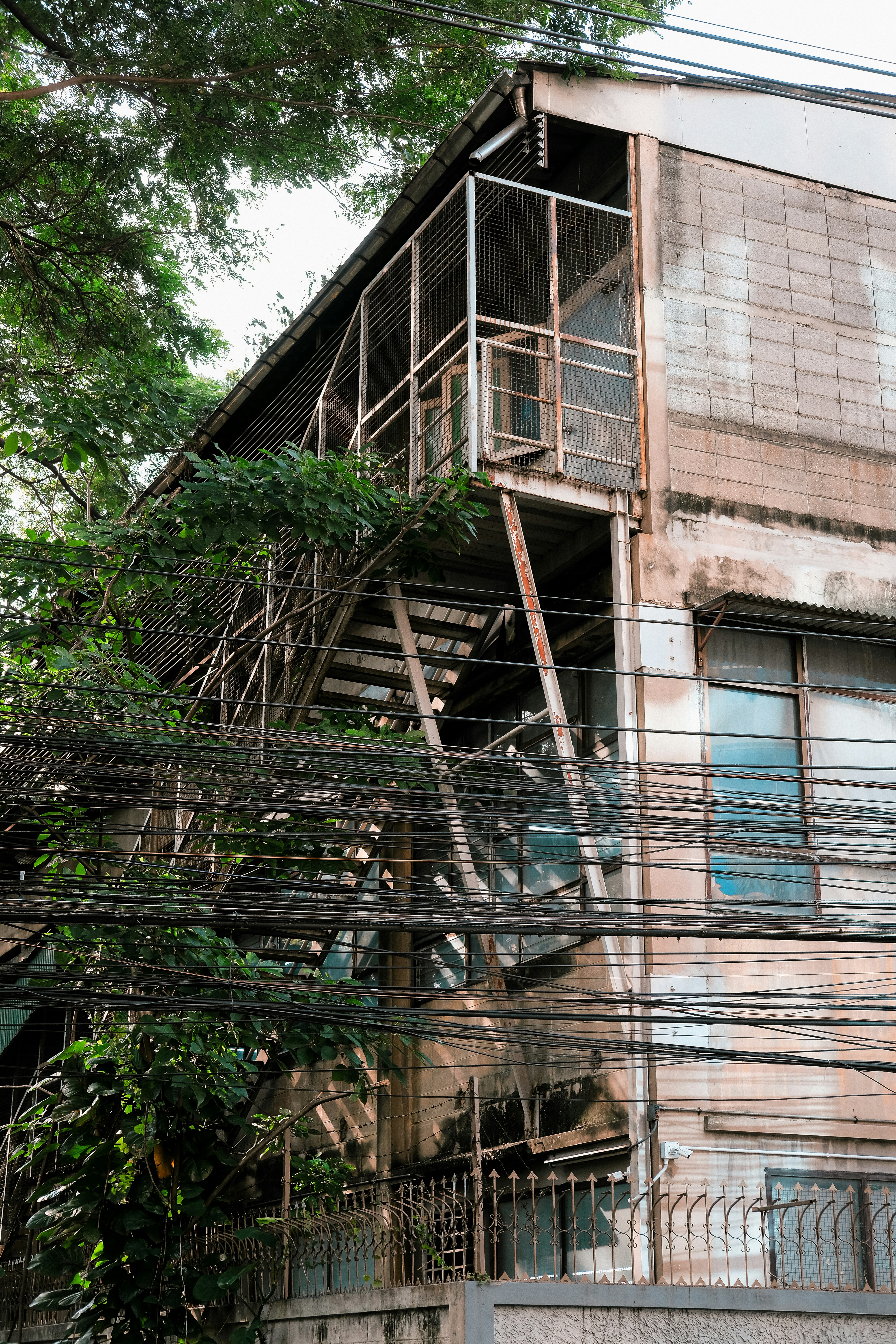 Rust and Wires: A Weathered Fire Escape Clings to a Faded Urban Facade