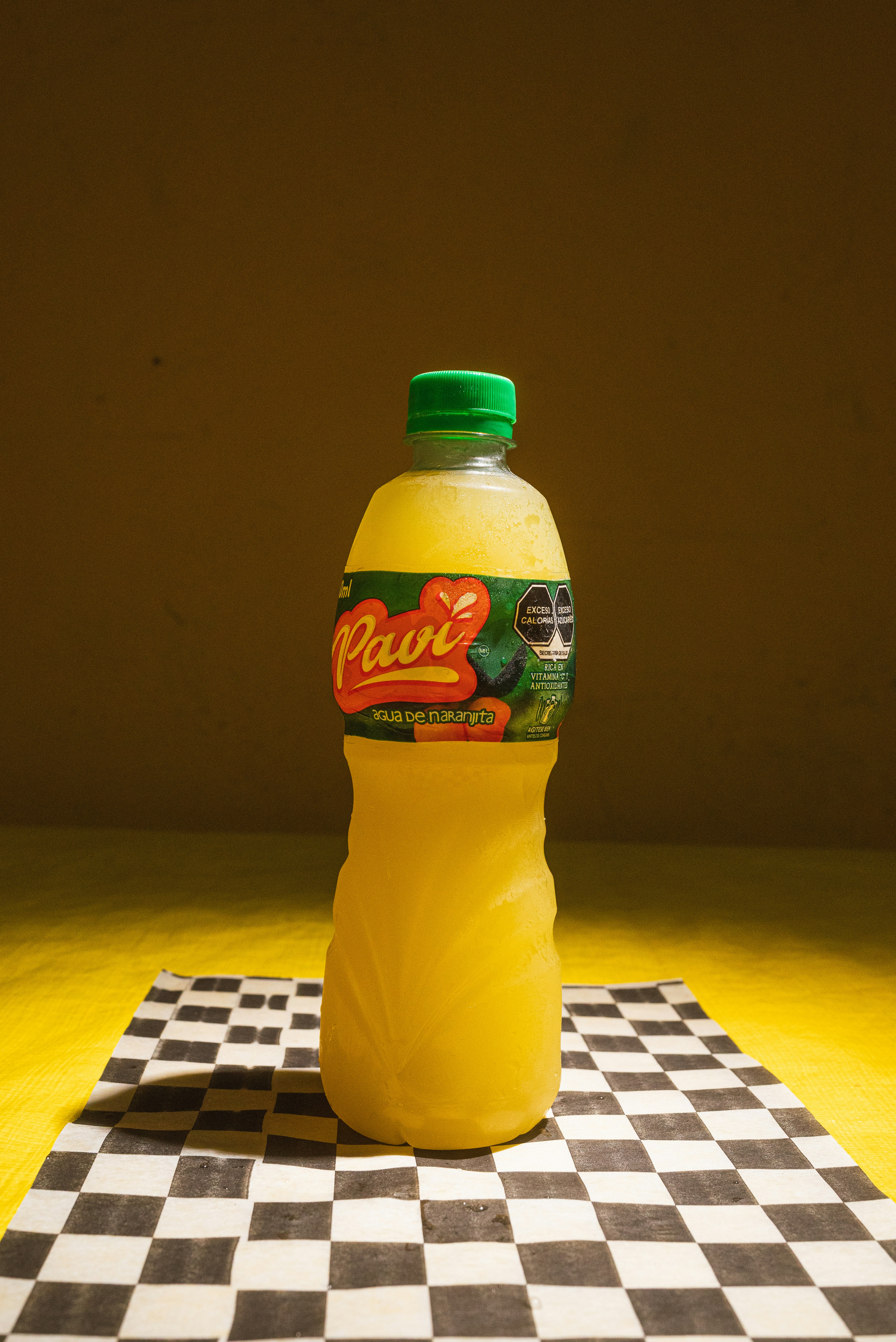 Amber Spotlight on a Checkered Stage: A Citrus Bottle Poised Under Warm Directional Light