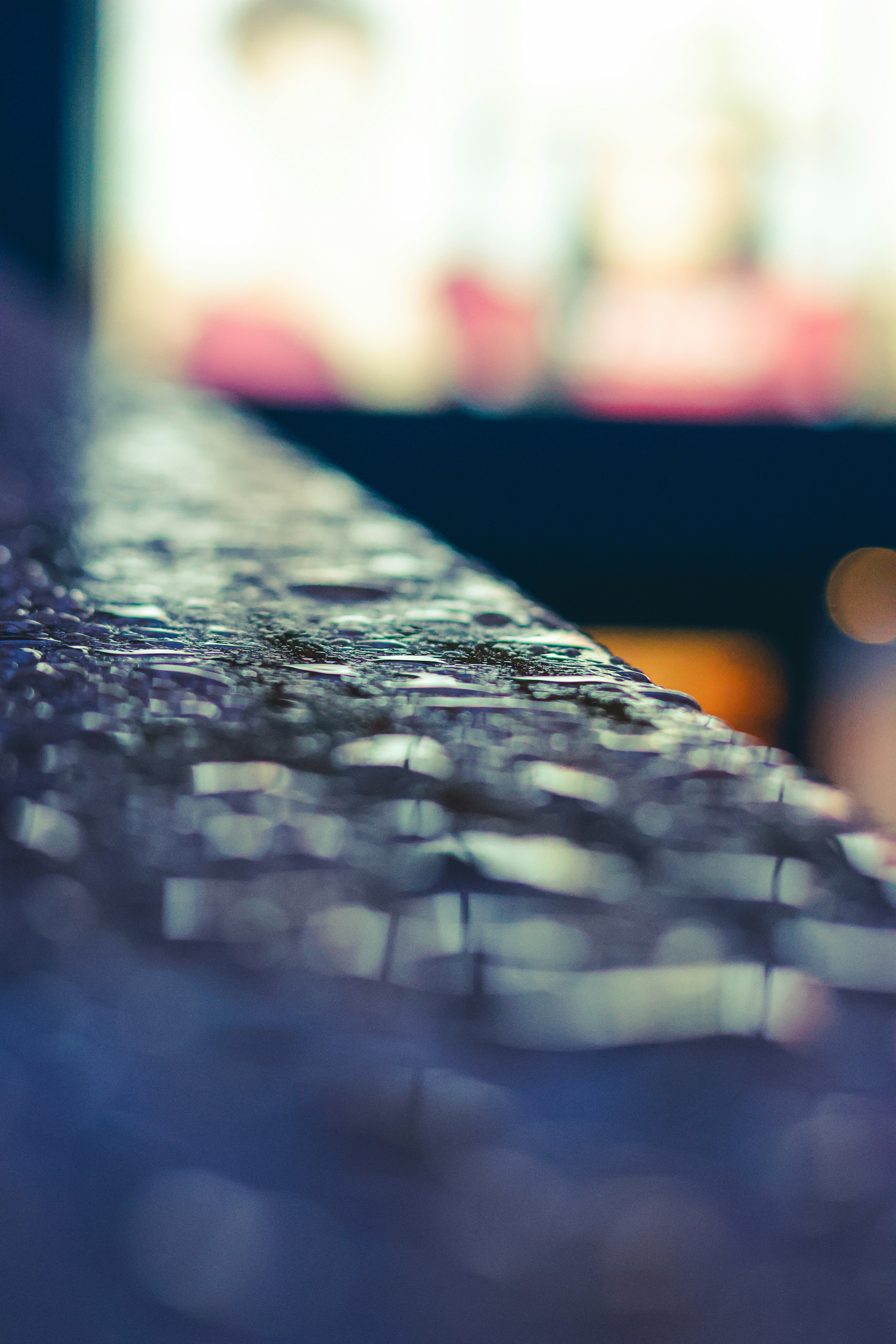 Low-Altitude Close-Up: Rain-Slicked Metal Railing Leading to a Blurred Background