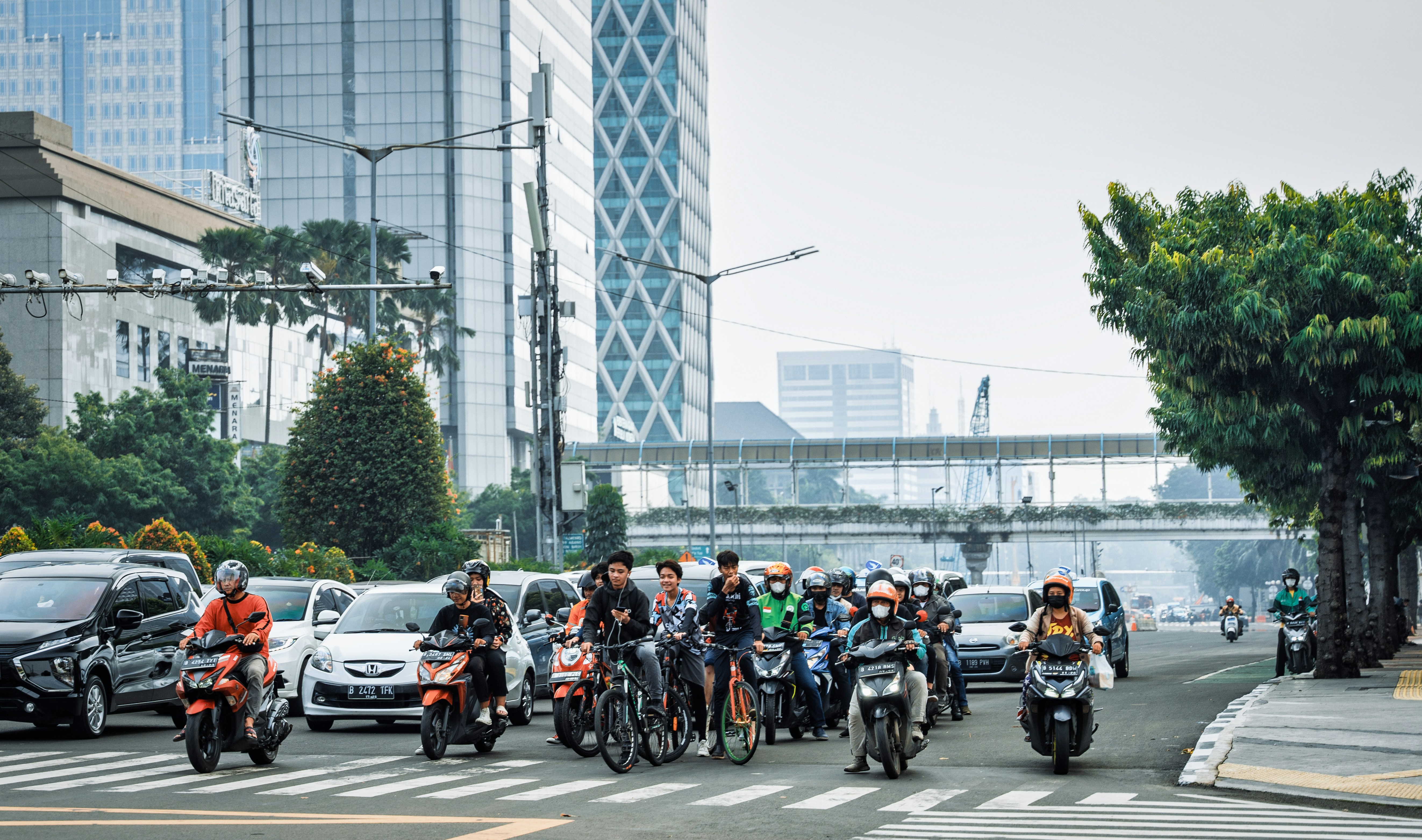 A group of people riding motorcycles down a street photo – Free Jakarta ...