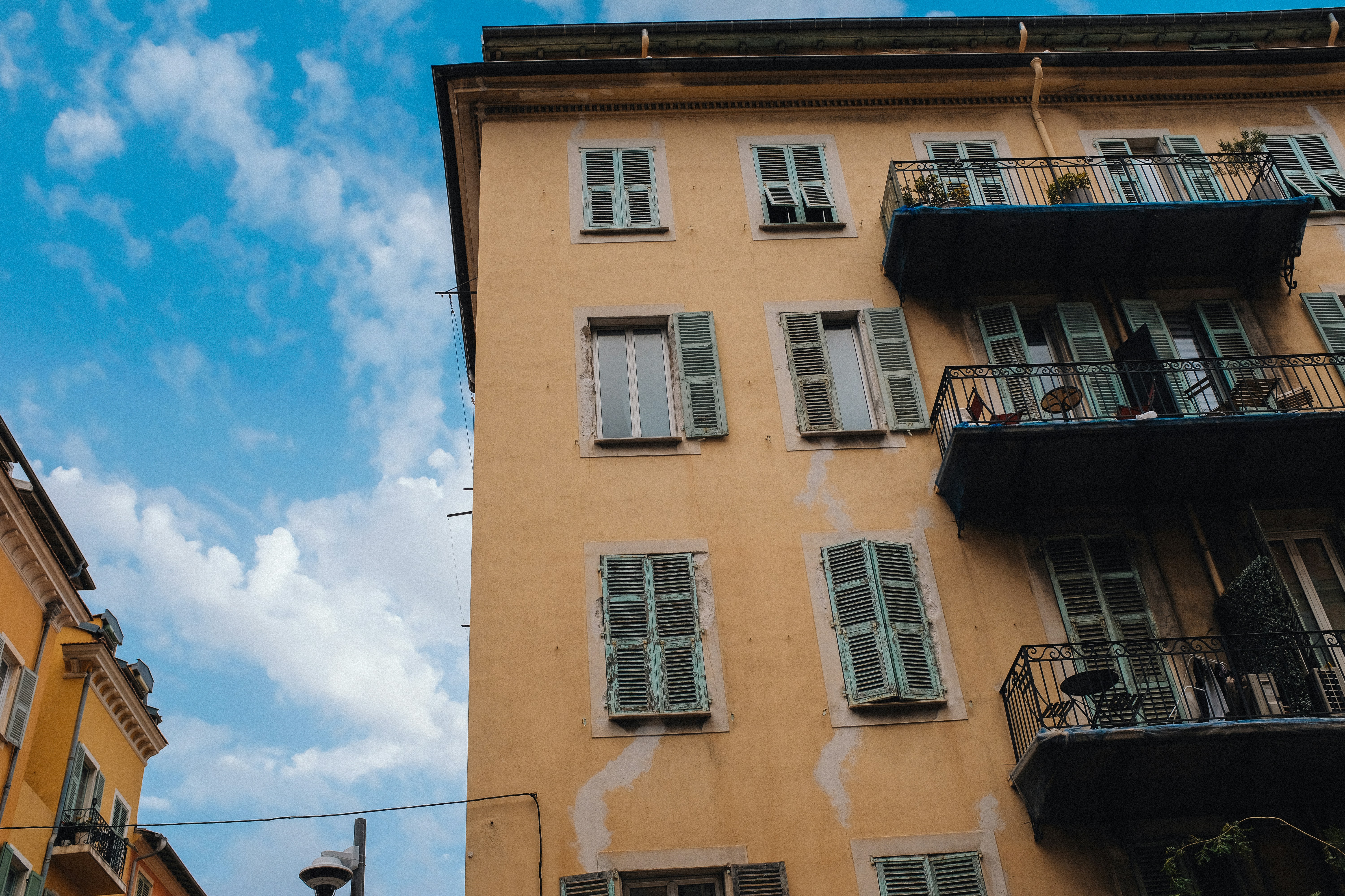 A tall yellow building with balconies and windows photo – Free City ...