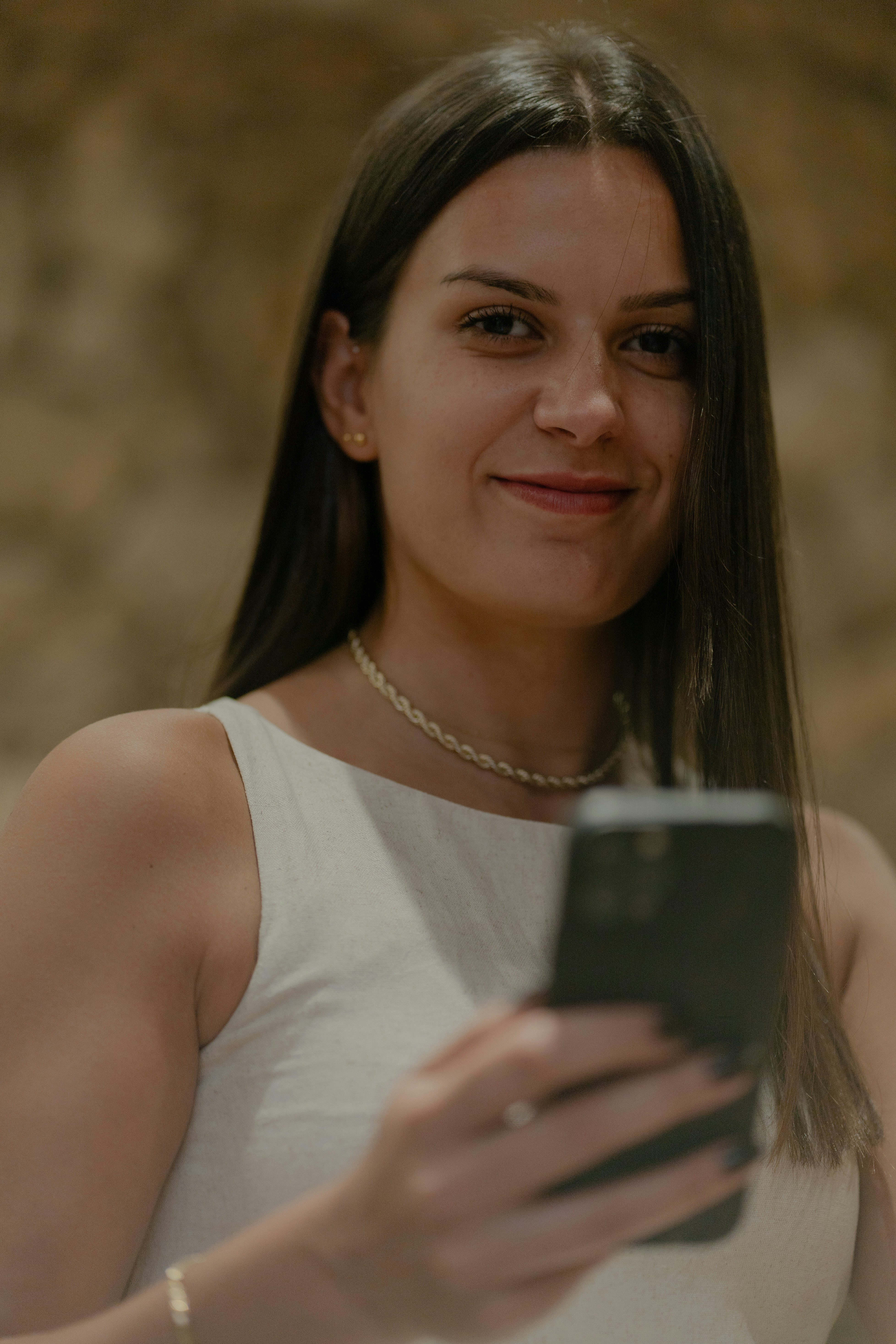 Amber-light portrait: a poised smile as she checks her phone