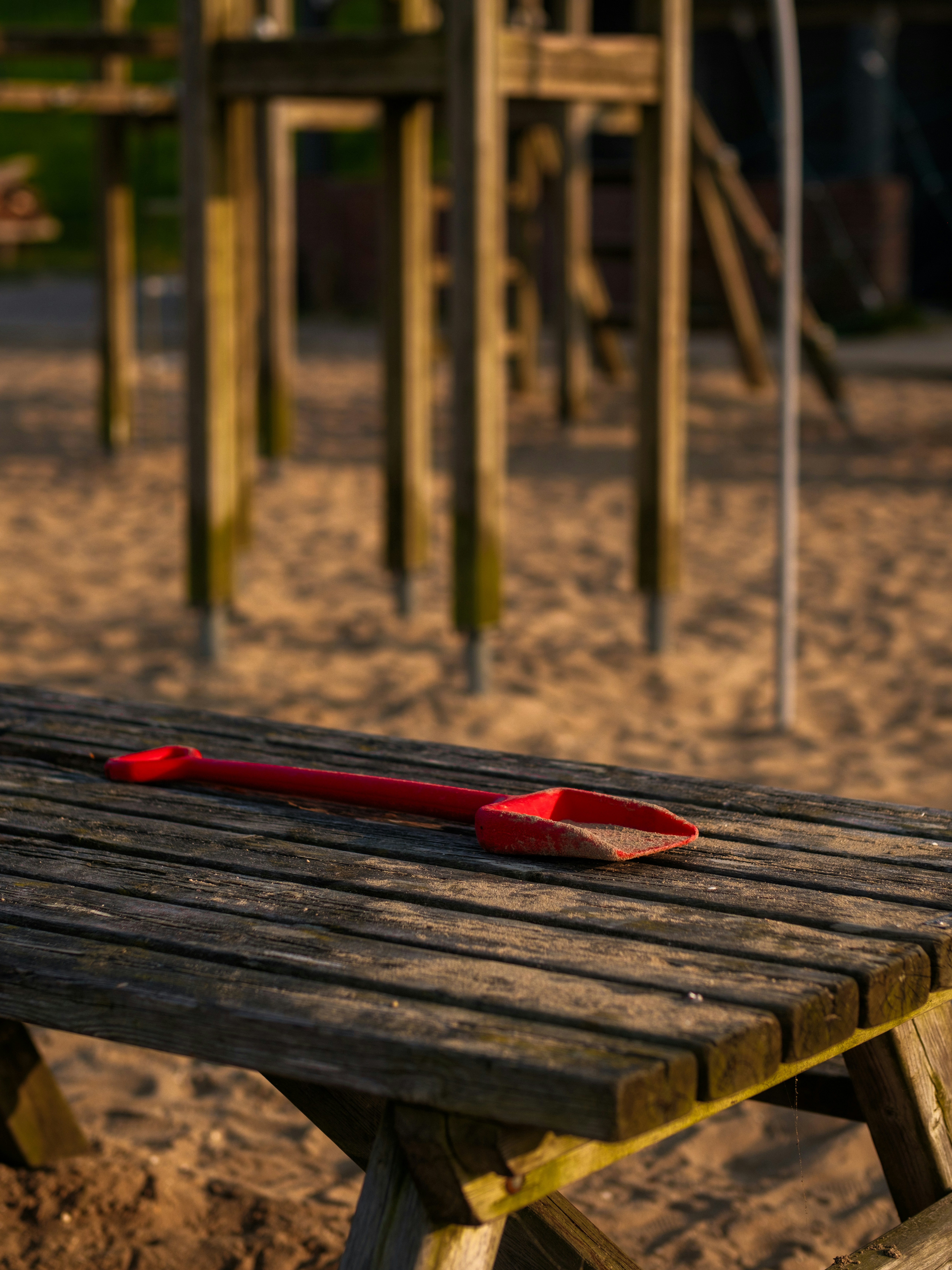 Red Sand Tool Resting on Weathered Picnic Table at Sunset