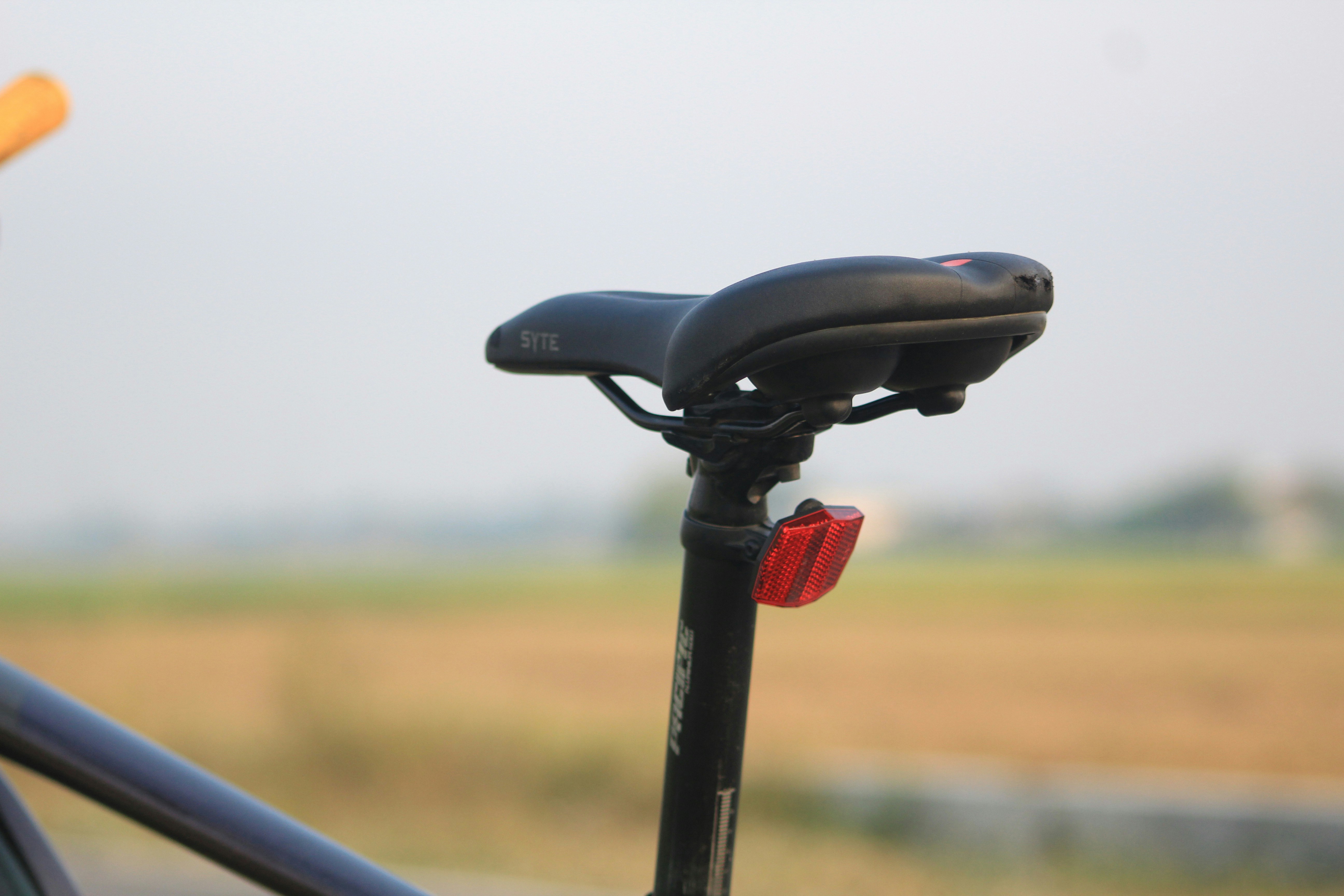 Saddle in Focus: A Quiet Road Bicycle Against a Sunlit Field