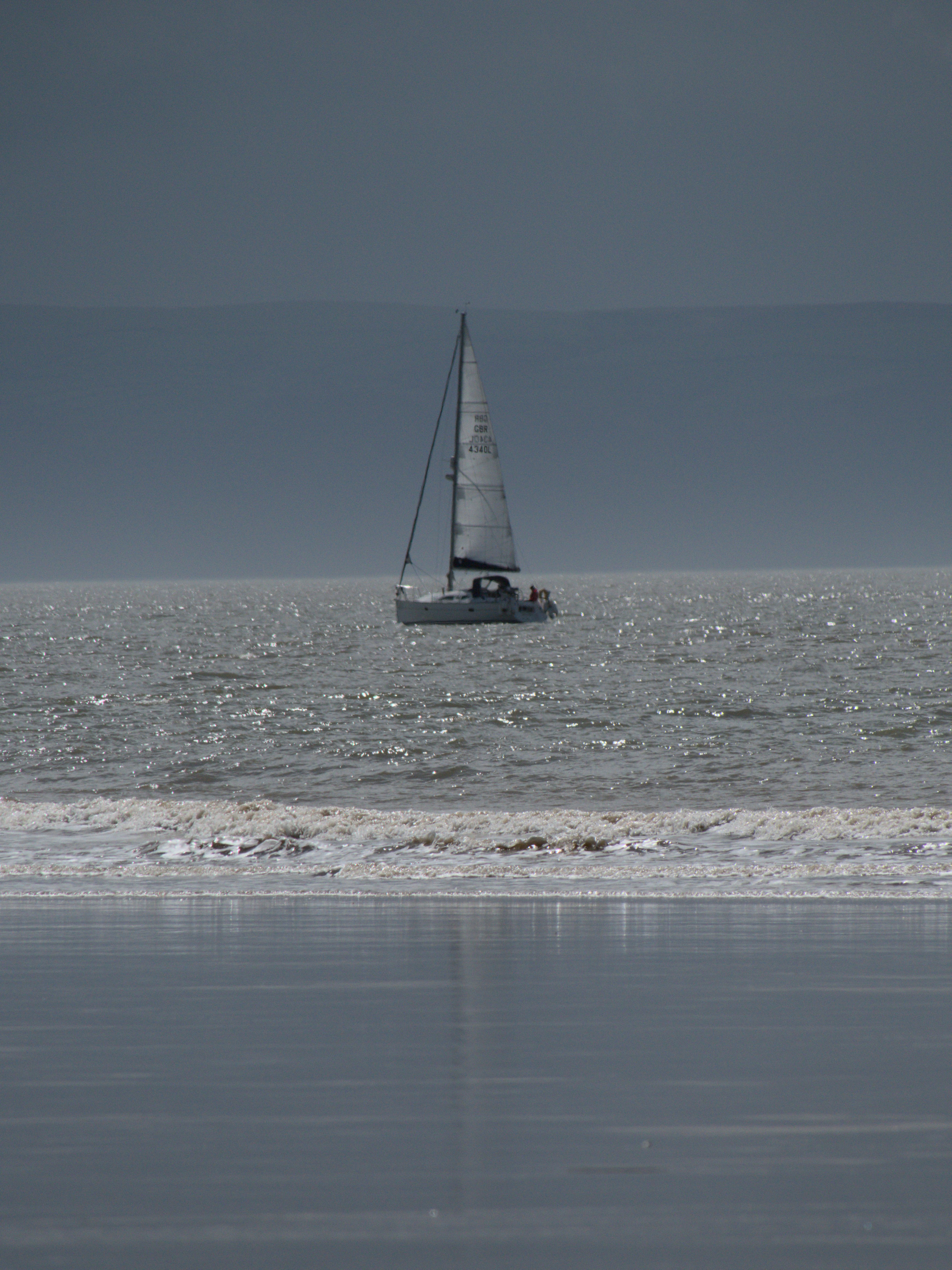 A sailboat in the ocean on a cloudy day photo – Free Beach Image on ...