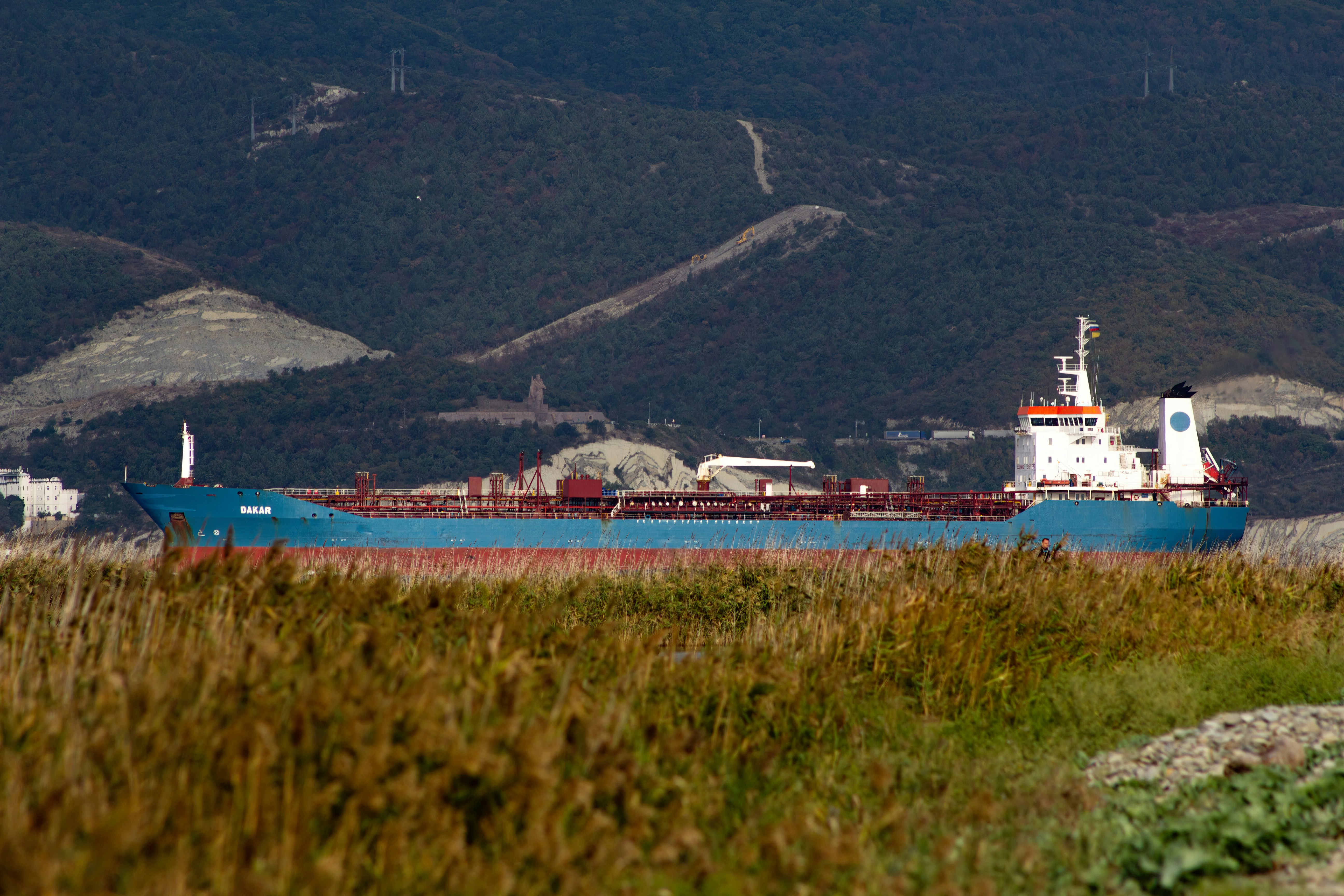 Blue Freighter on a Meadow Stage: Cargo Vessel Framed by Mountains