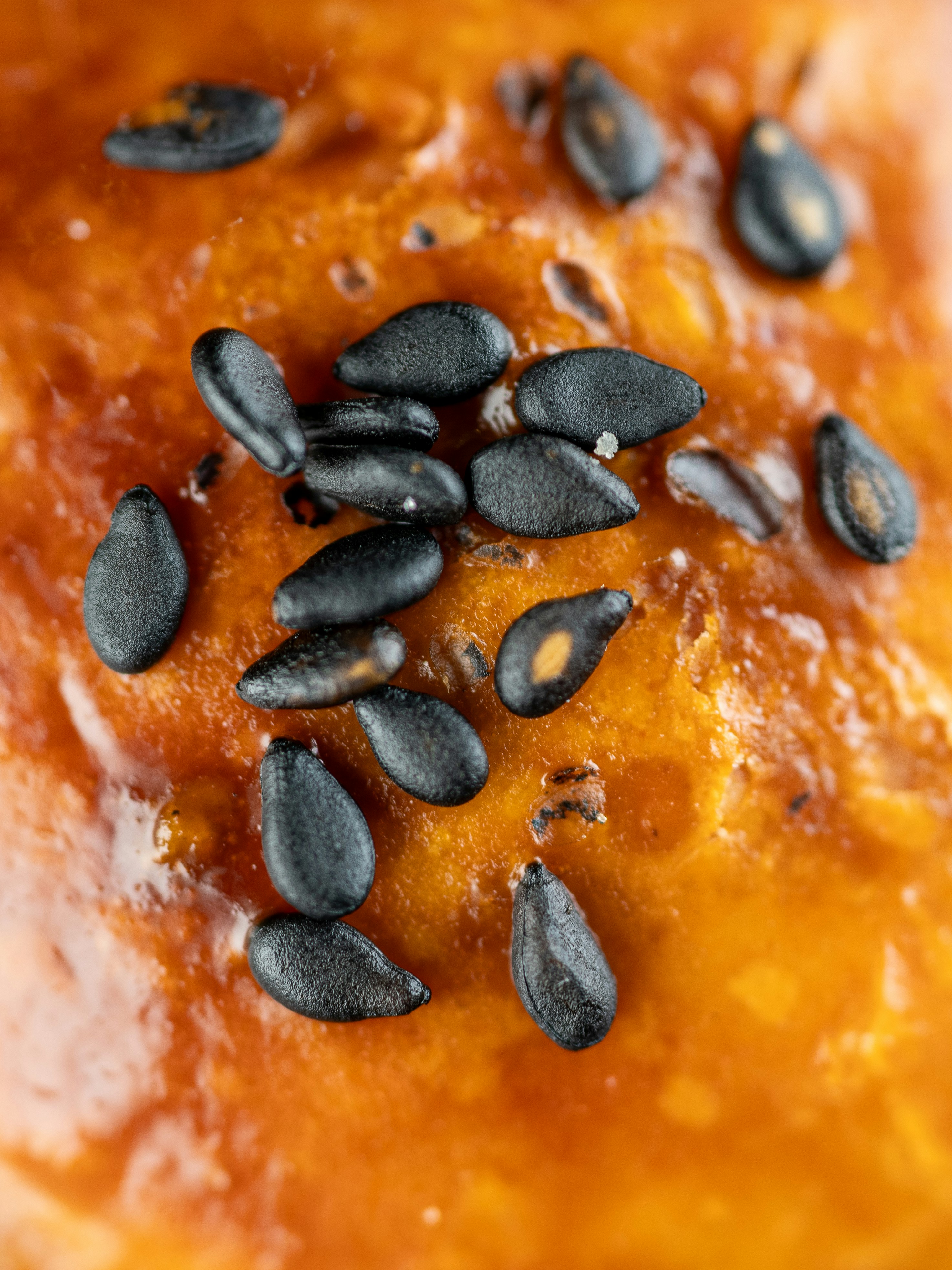 Seeded Ember: a macro close-up of orange glaze dotted with black sesame seeds