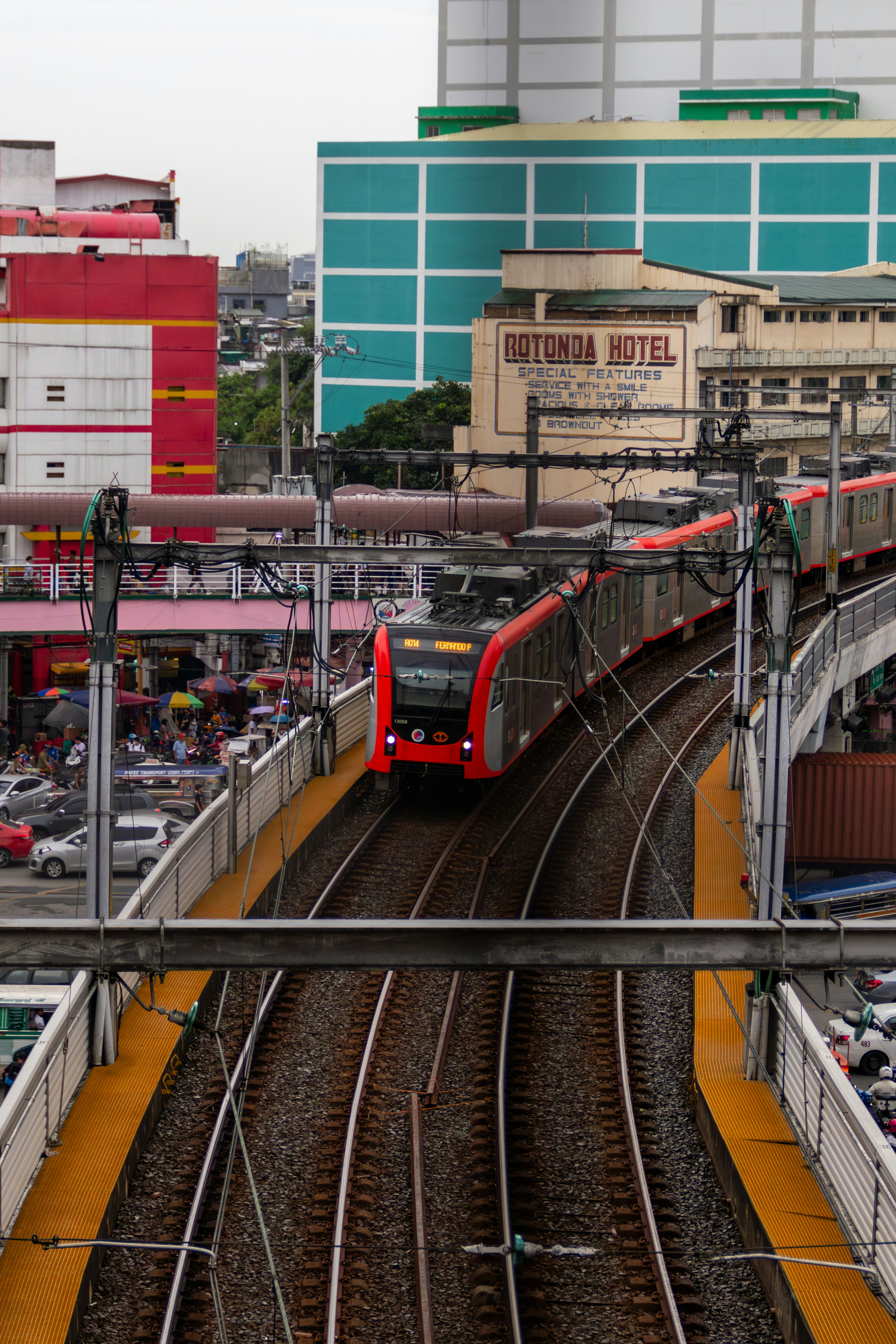 A red train traveling down train tracks next to tall buildings