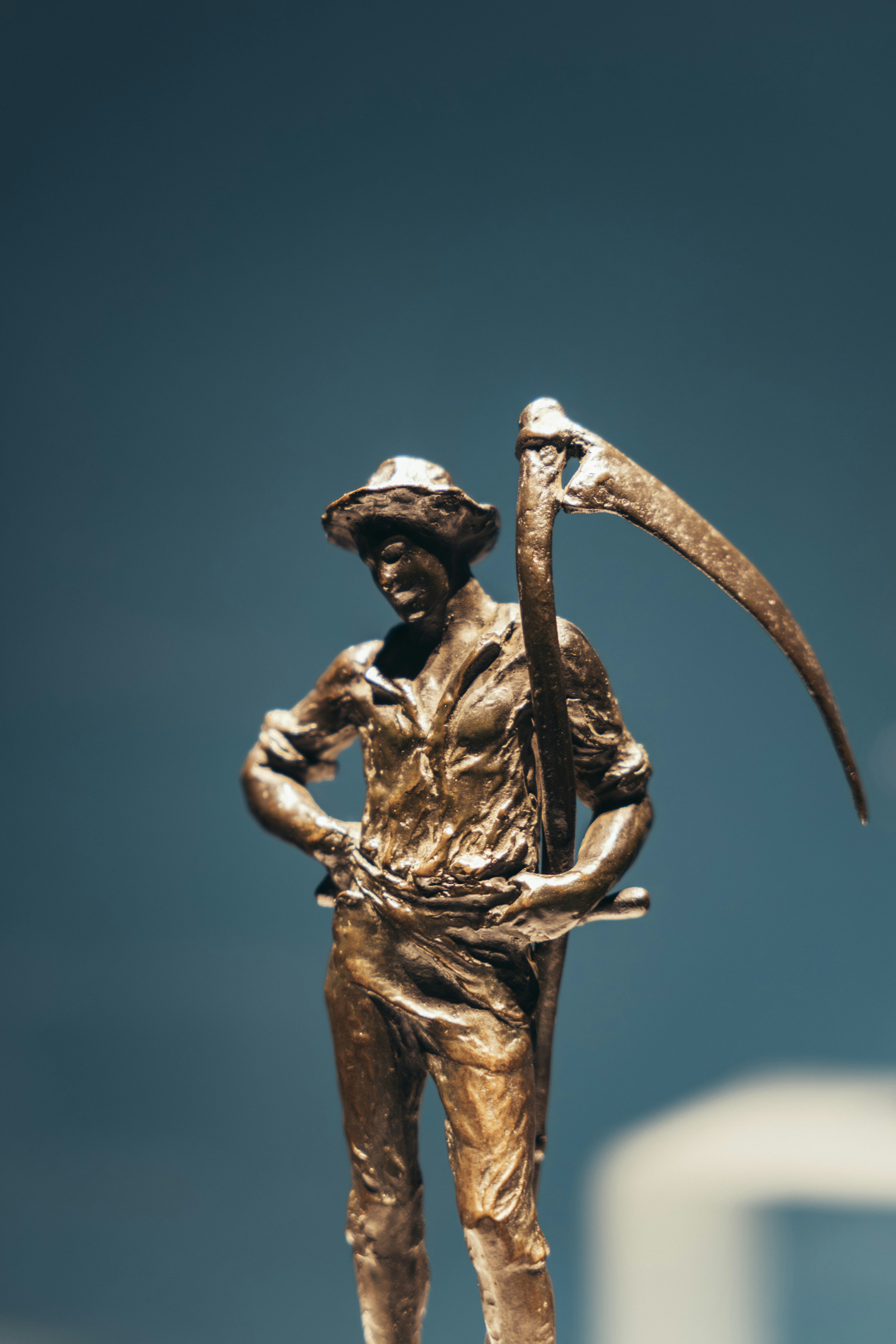 Bronze Pathfinder: A Solitary Figure with Scythe Embracing the Blue Backdrop