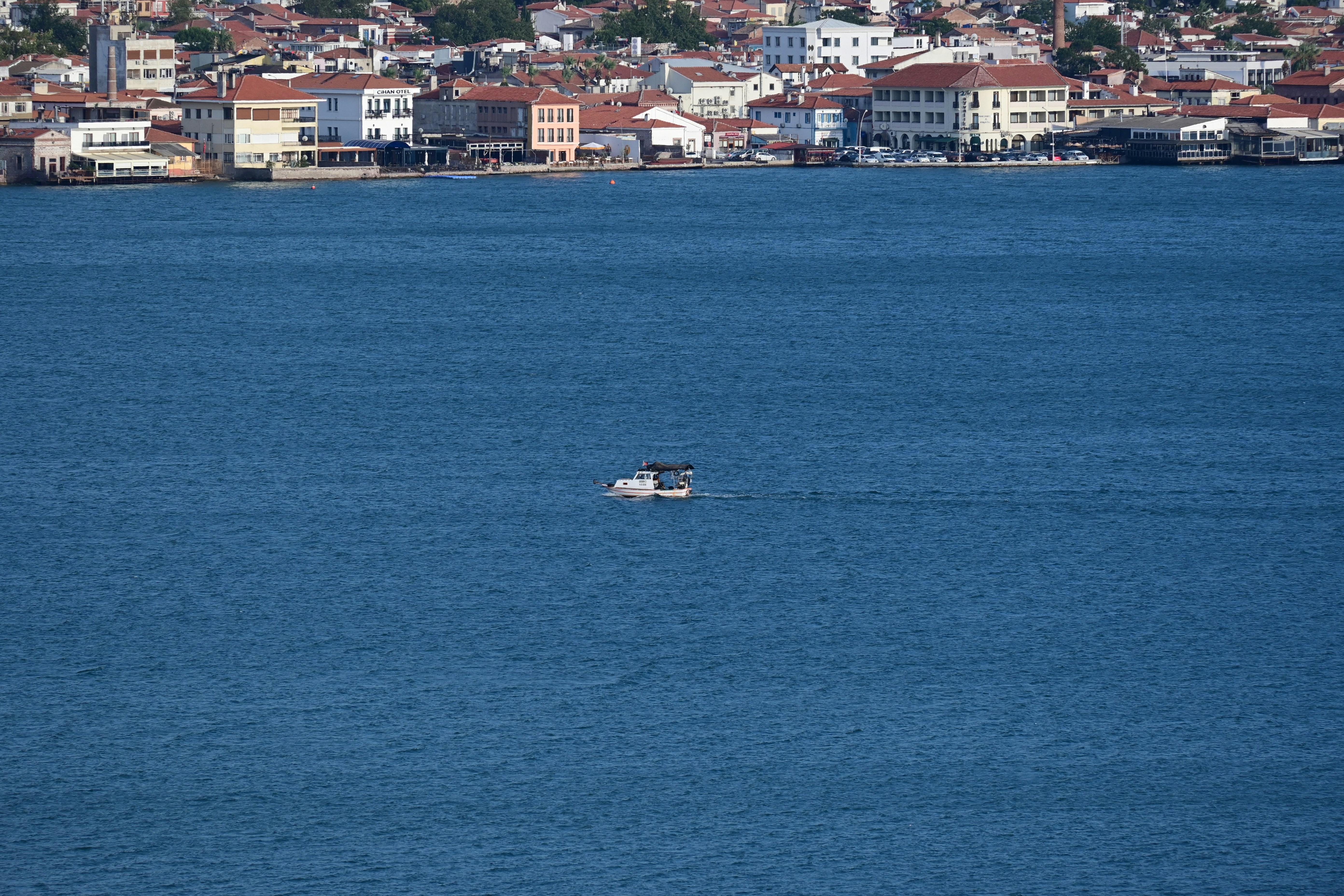 Lone Vessel Skims a Quiet Cerulean Channel Toward a Distant Harbor