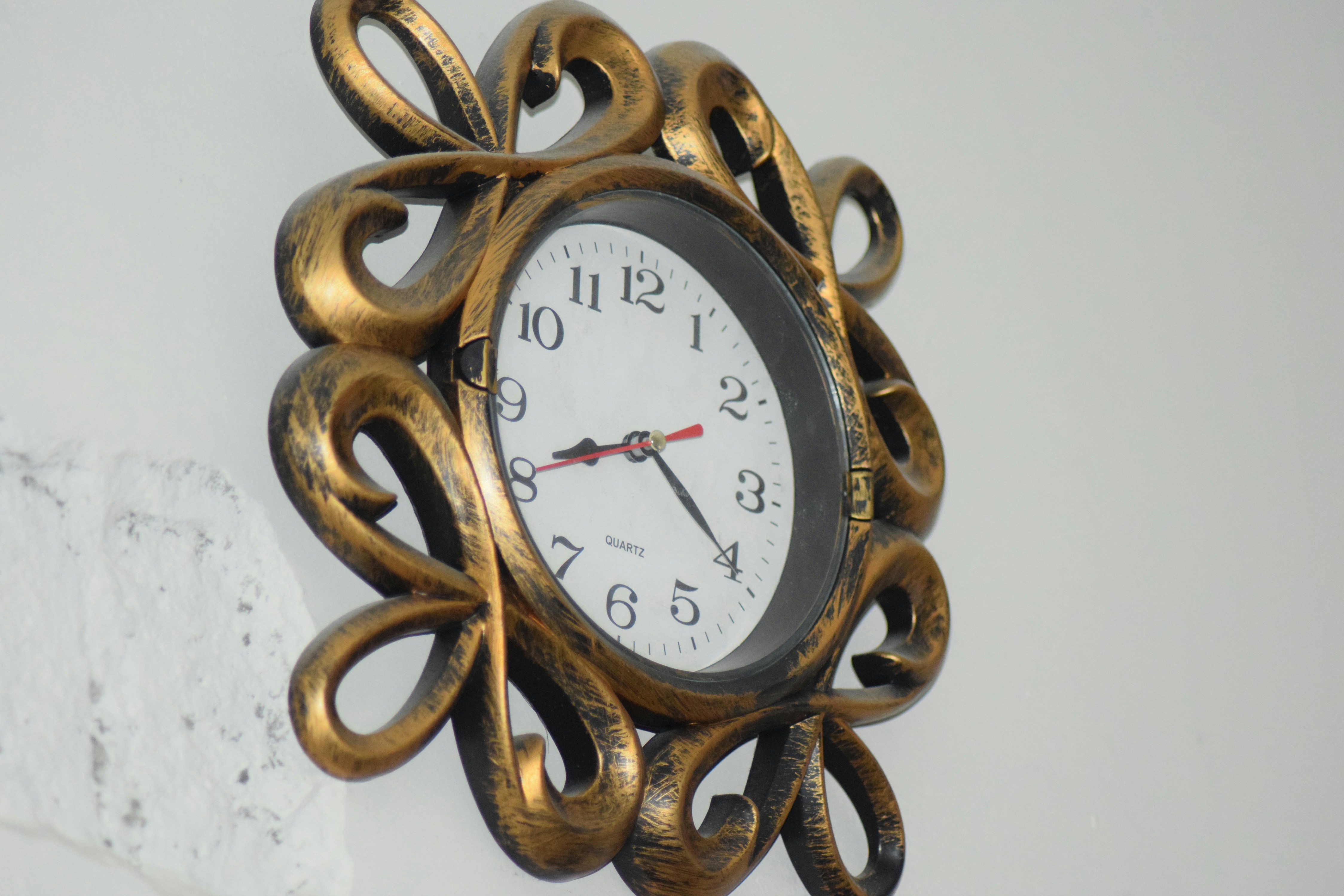 Bronze Loopclock: Time Woven in a Floral Ring on a Pale Wall