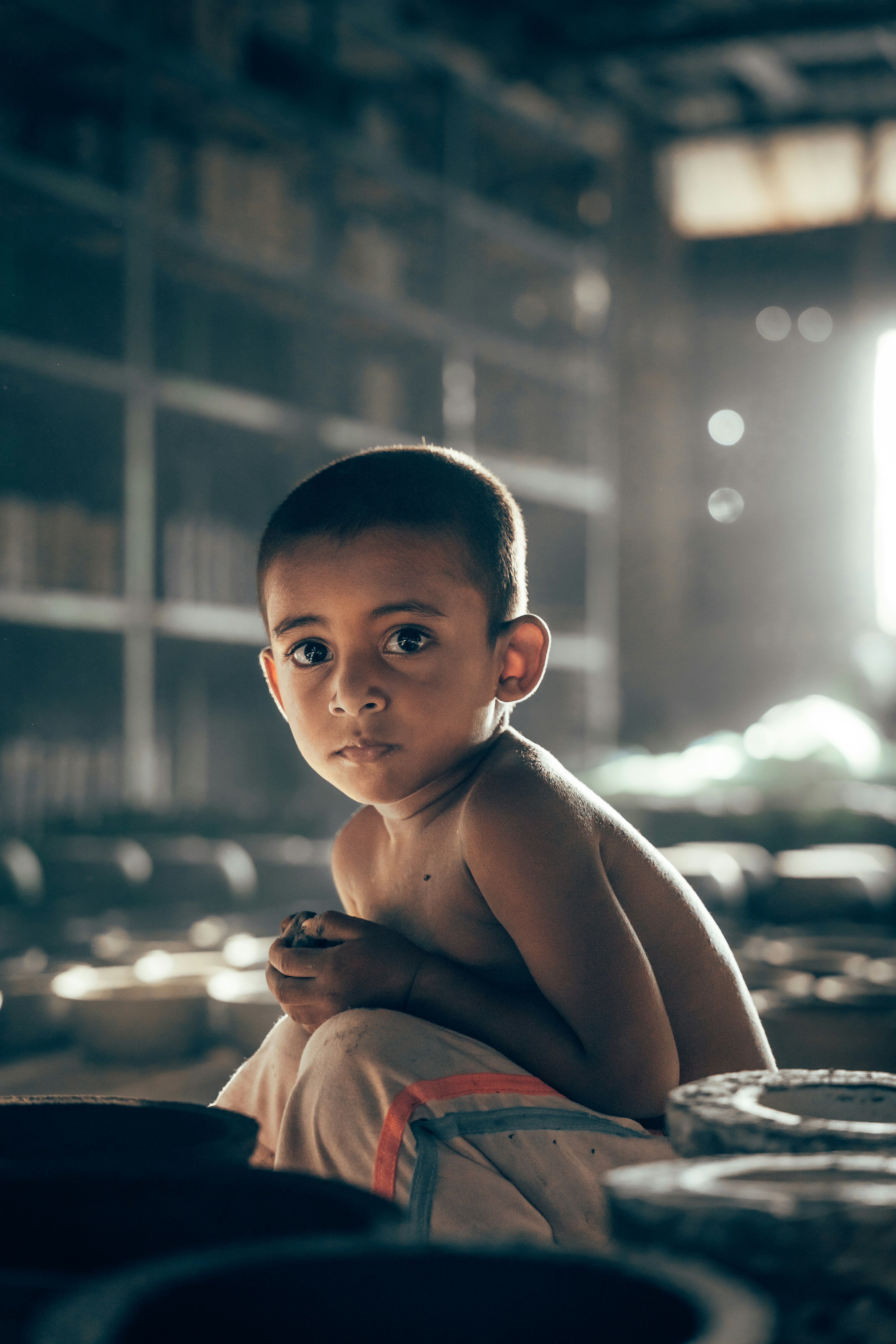 A young boy sitting on the ground in a warehouse photo – Free Comilla Image on Unsplash
