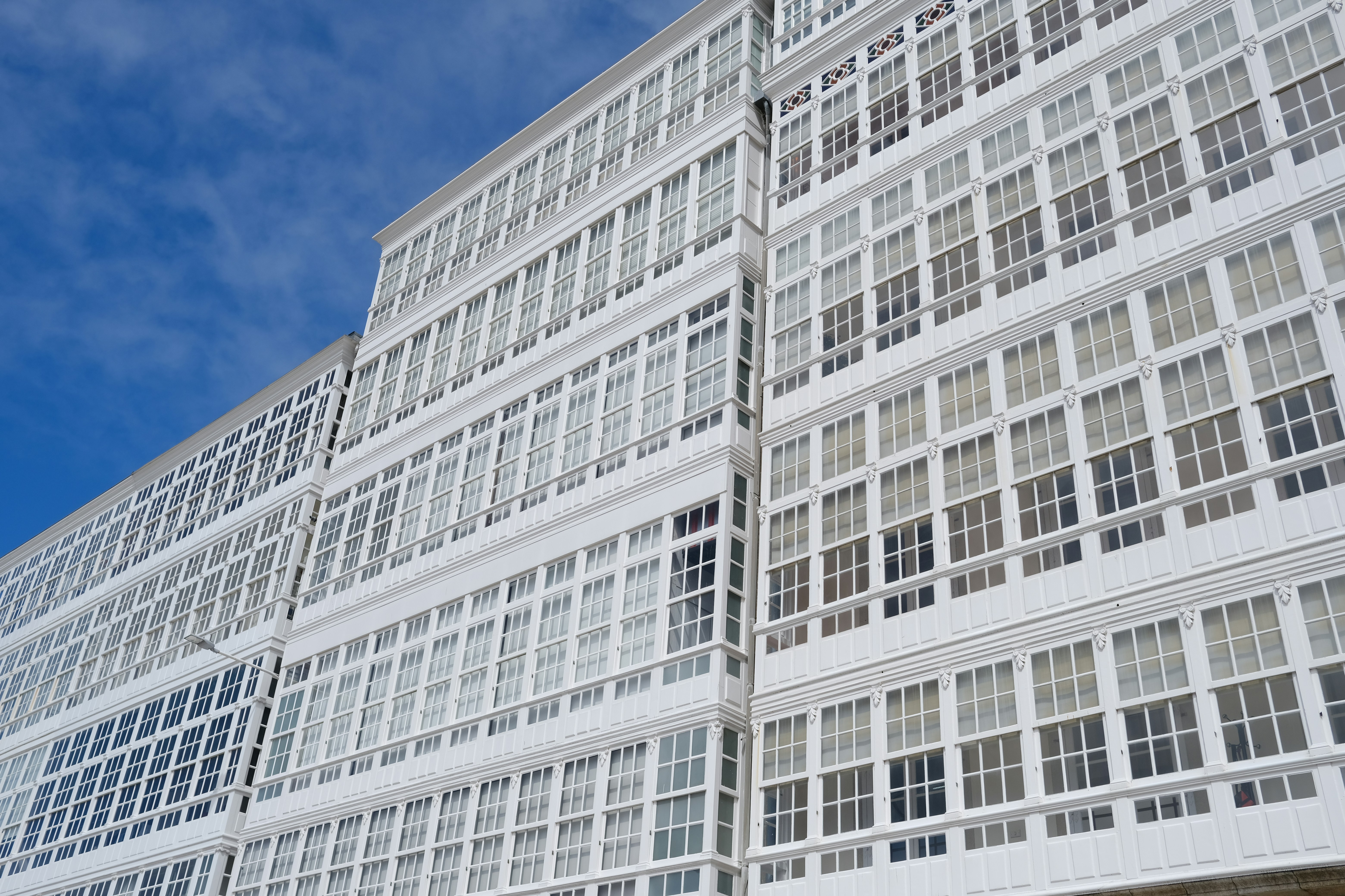 White building facade with numerous symmetrical windows under a clear blue sky.