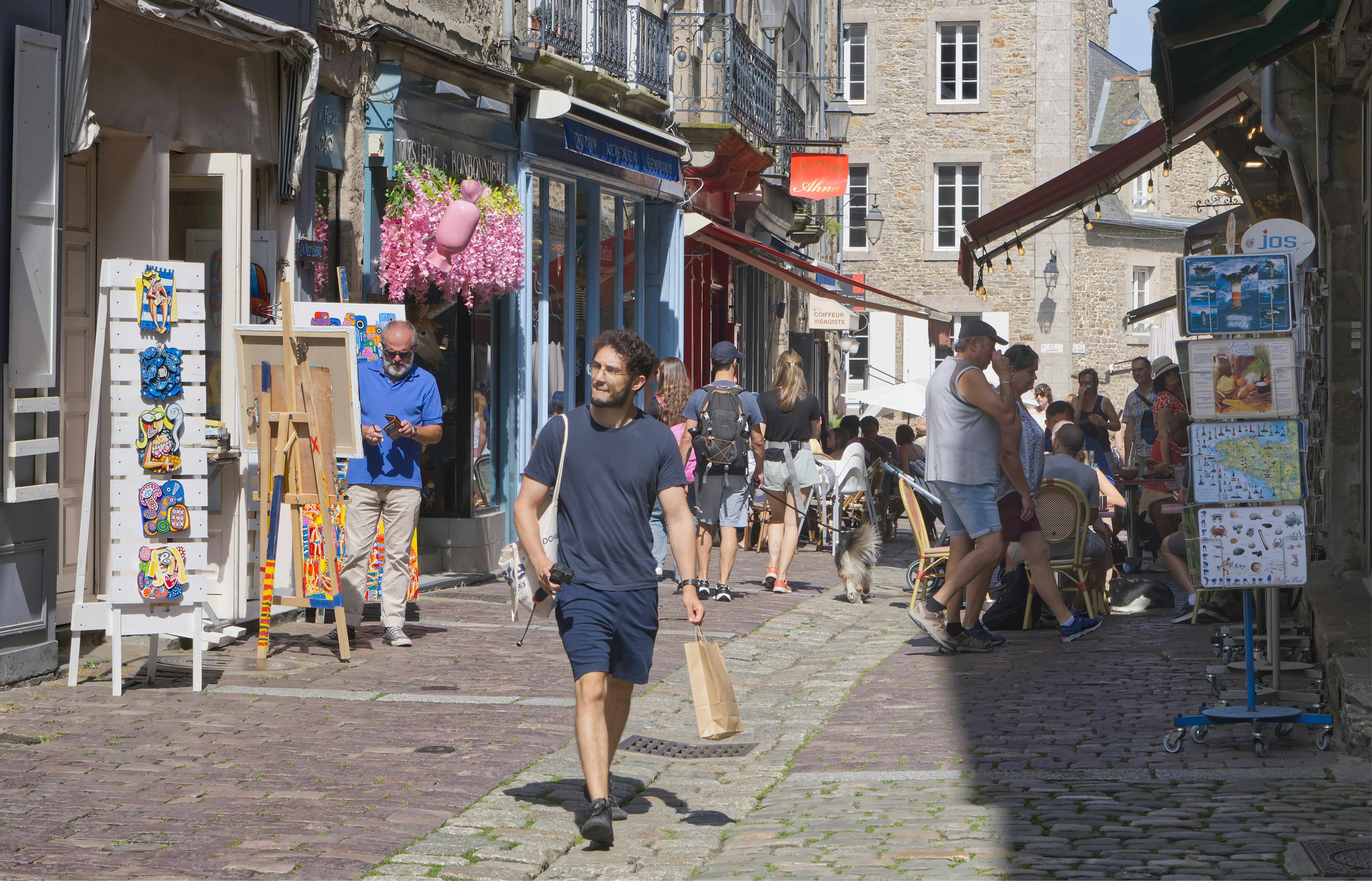 Blue-Shirt Wanderer Navigates a Bustling Cobblestone Market at Noon