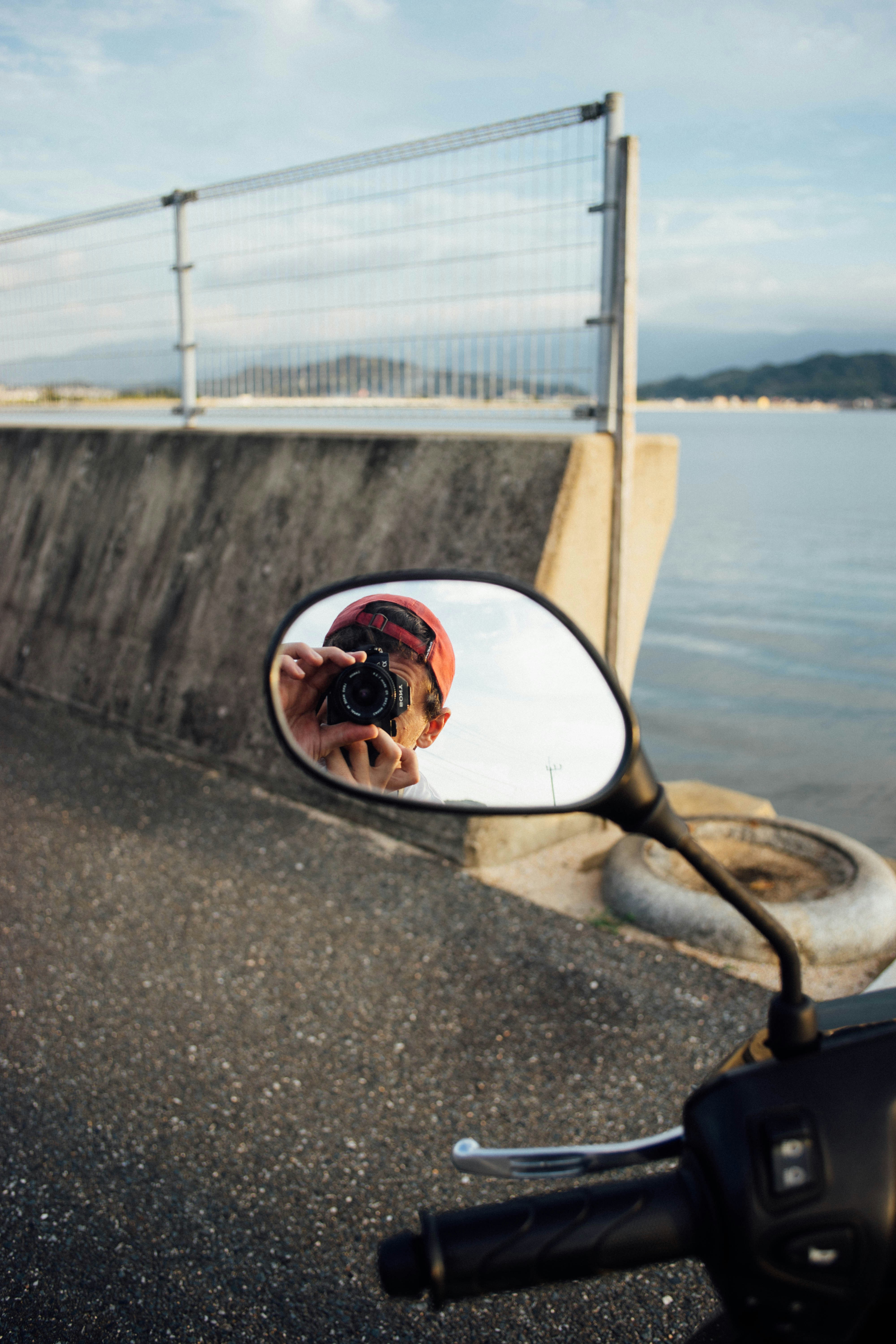 Seaside Reflections: A Photographer in a Motorcycle Mirror