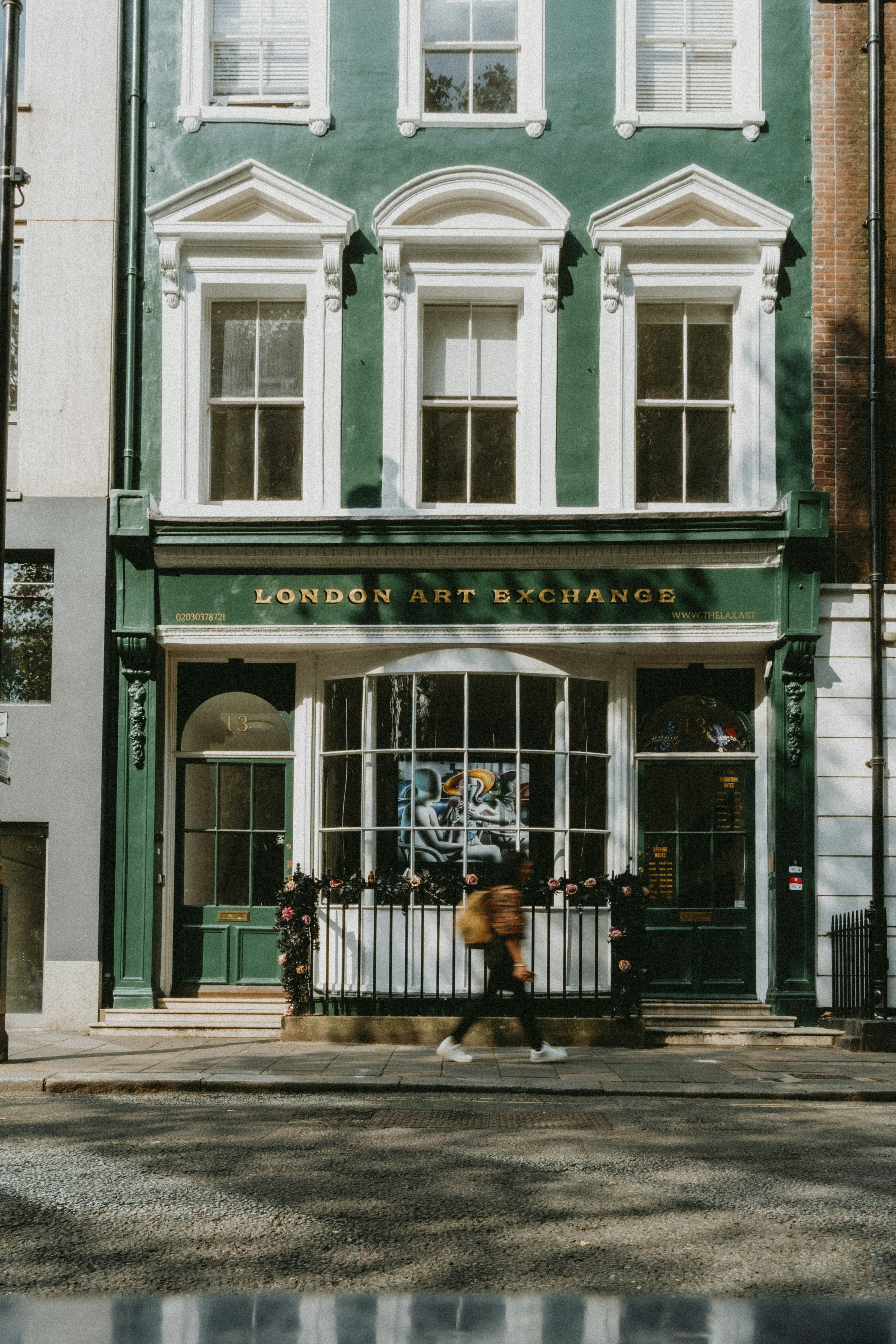 A man walking past a tall green and white building