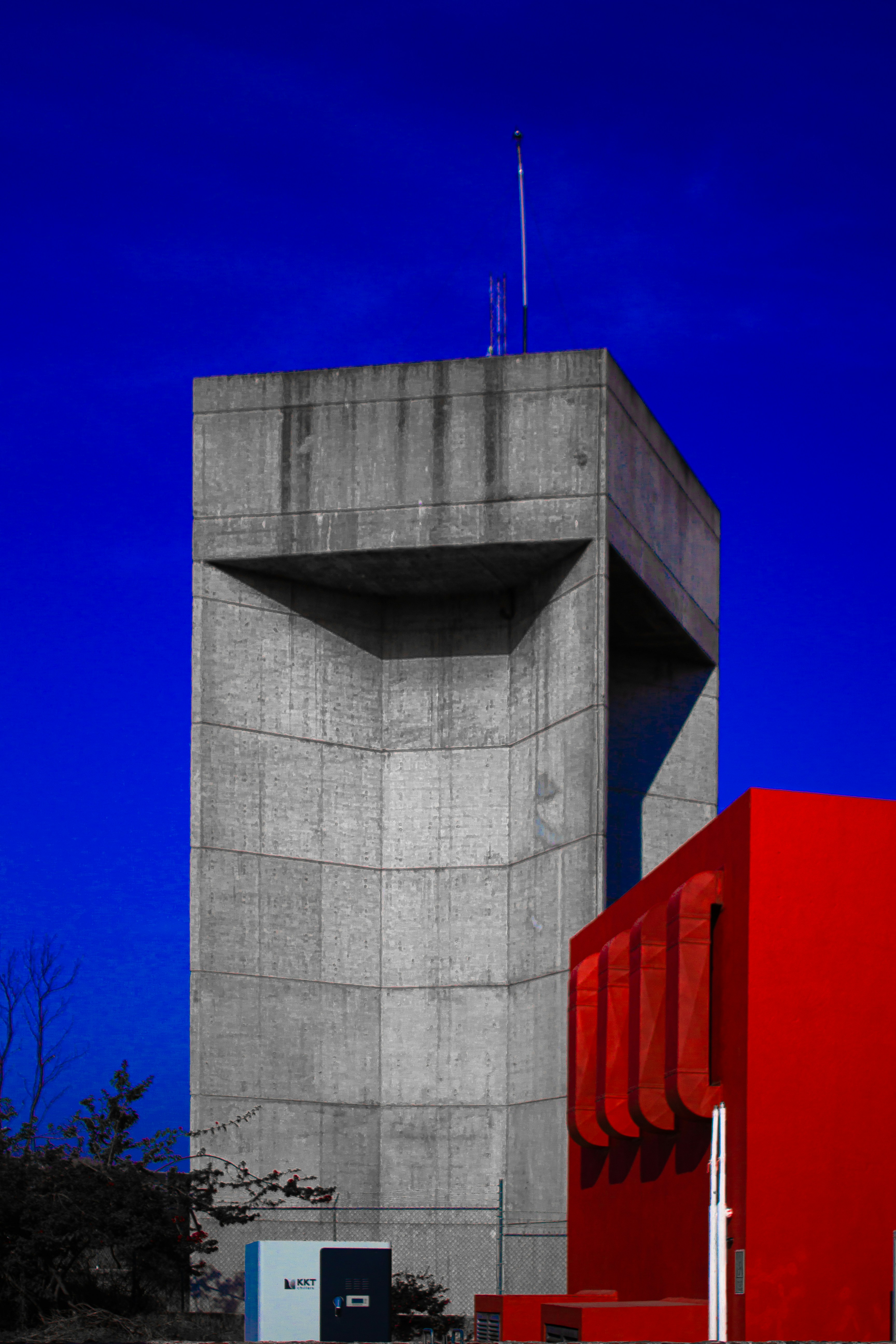Concrete tower rises above a bold red annex under a cobalt sky