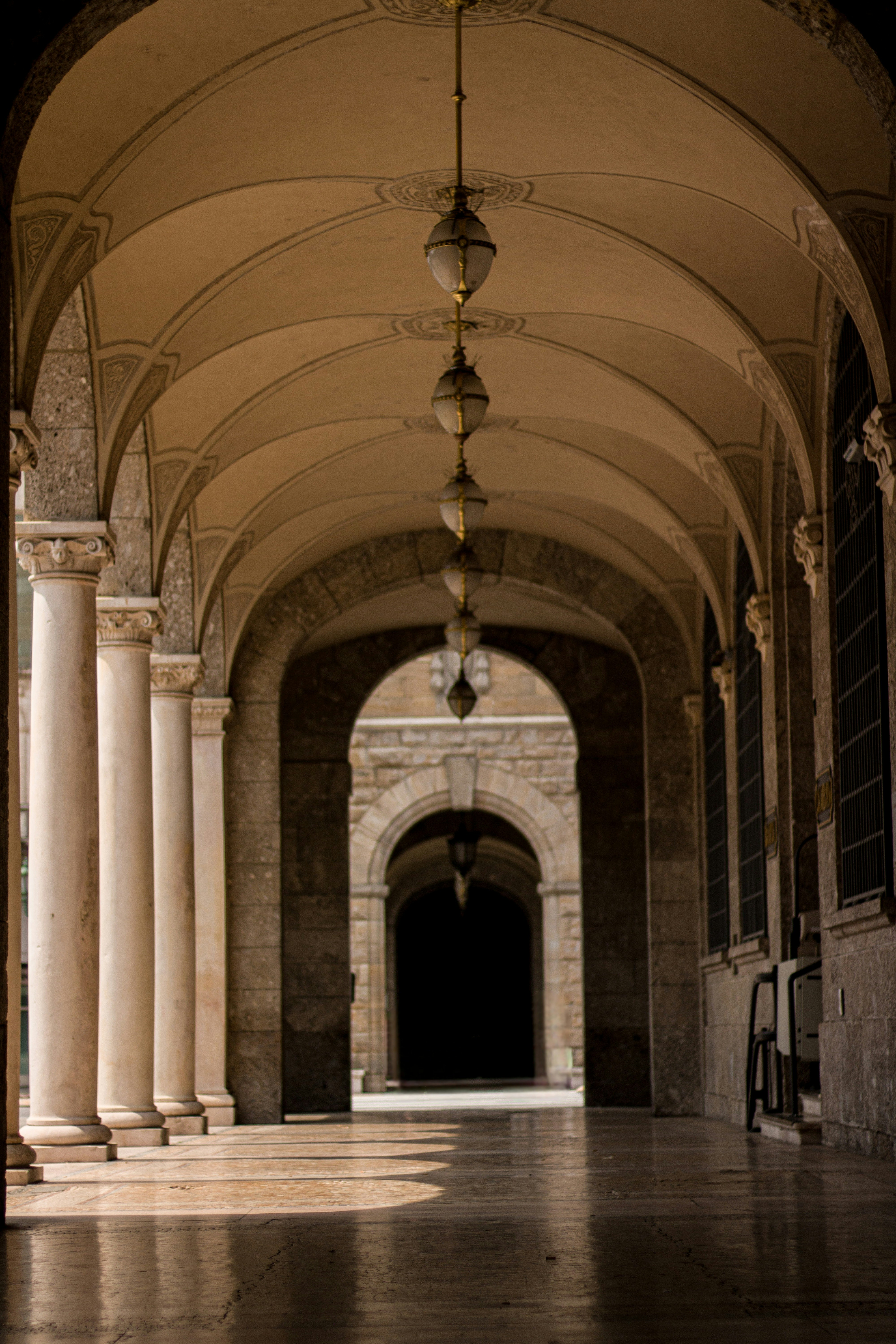 A hallway with columns and a clock on the wall photo – Free Italy Image ...