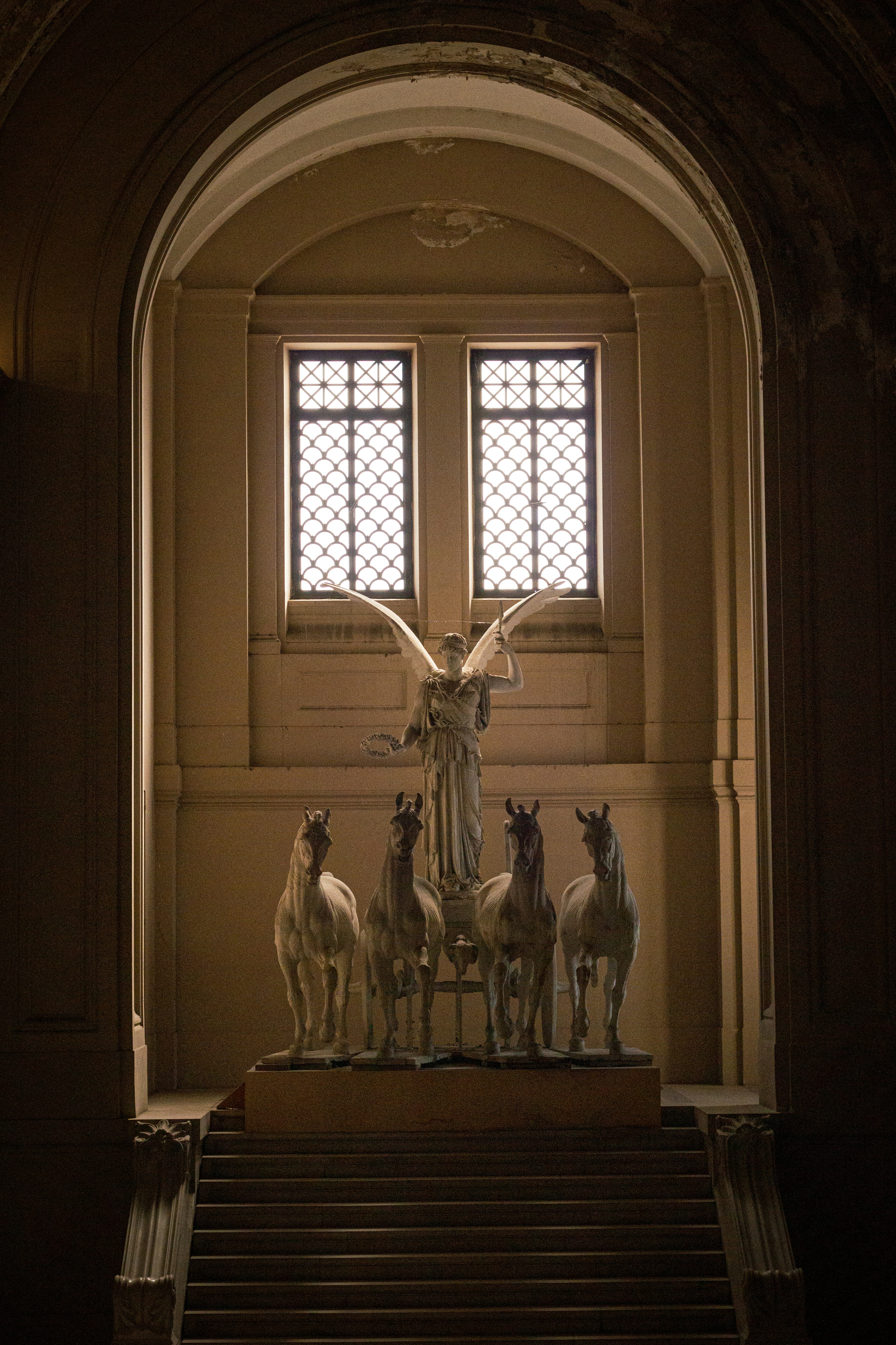 Winged Allegory Over a Four-Horse Pedestal in a Dim Hall