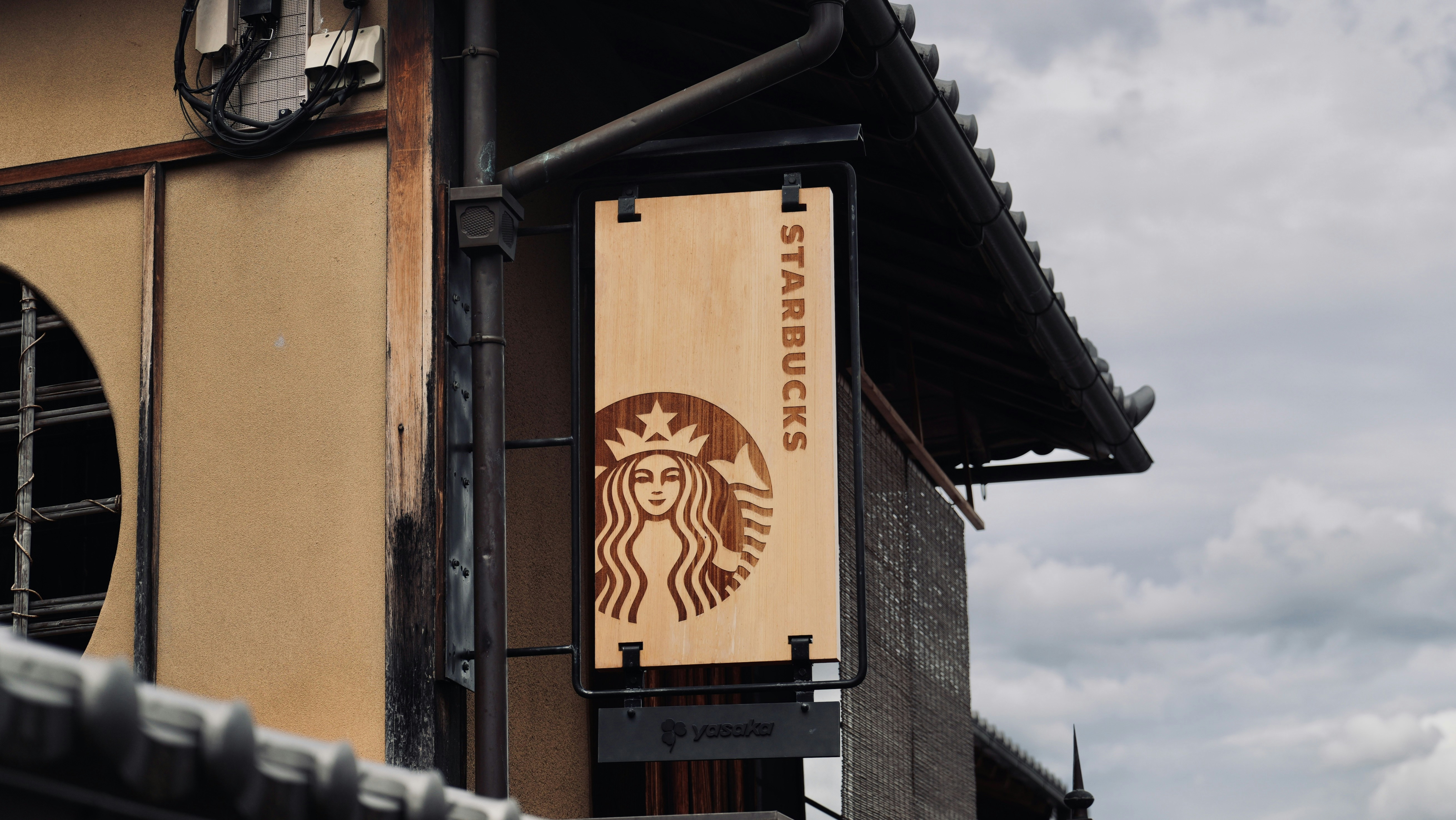 A starbucks sign hanging from the side of a building photo – Free Woman ...