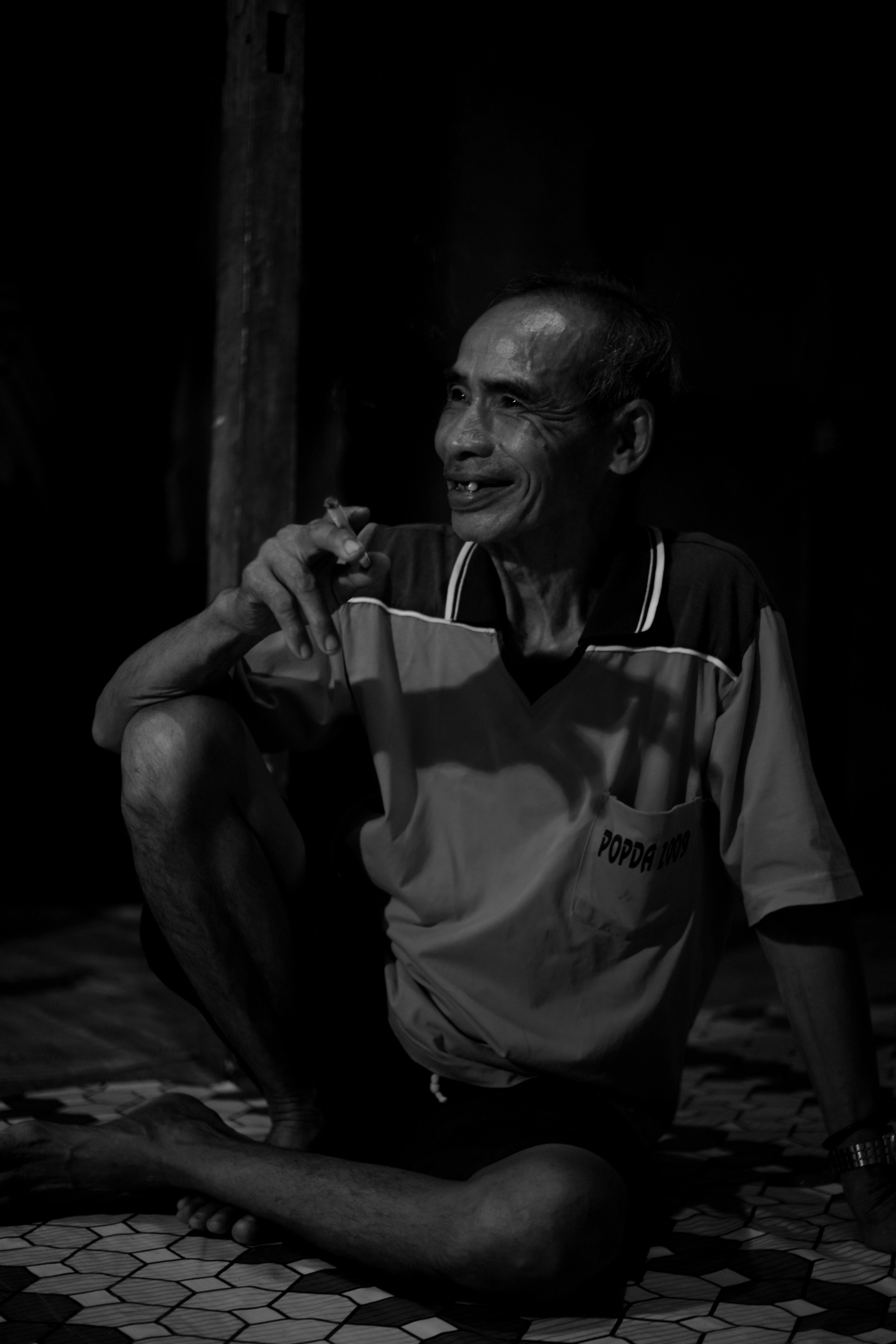 A man sitting on the ground smoking a cigarette photo – Free Portrait ...