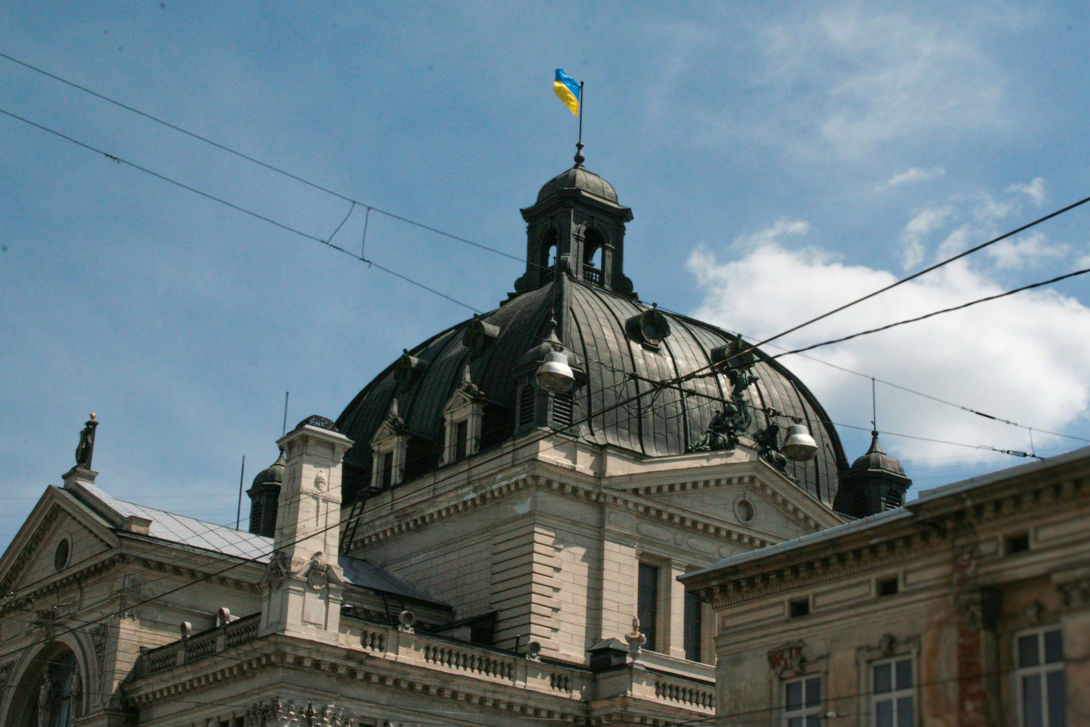 Flag-Crowned Dome: Sunlit City Hall Surrounded by Tram Wires
