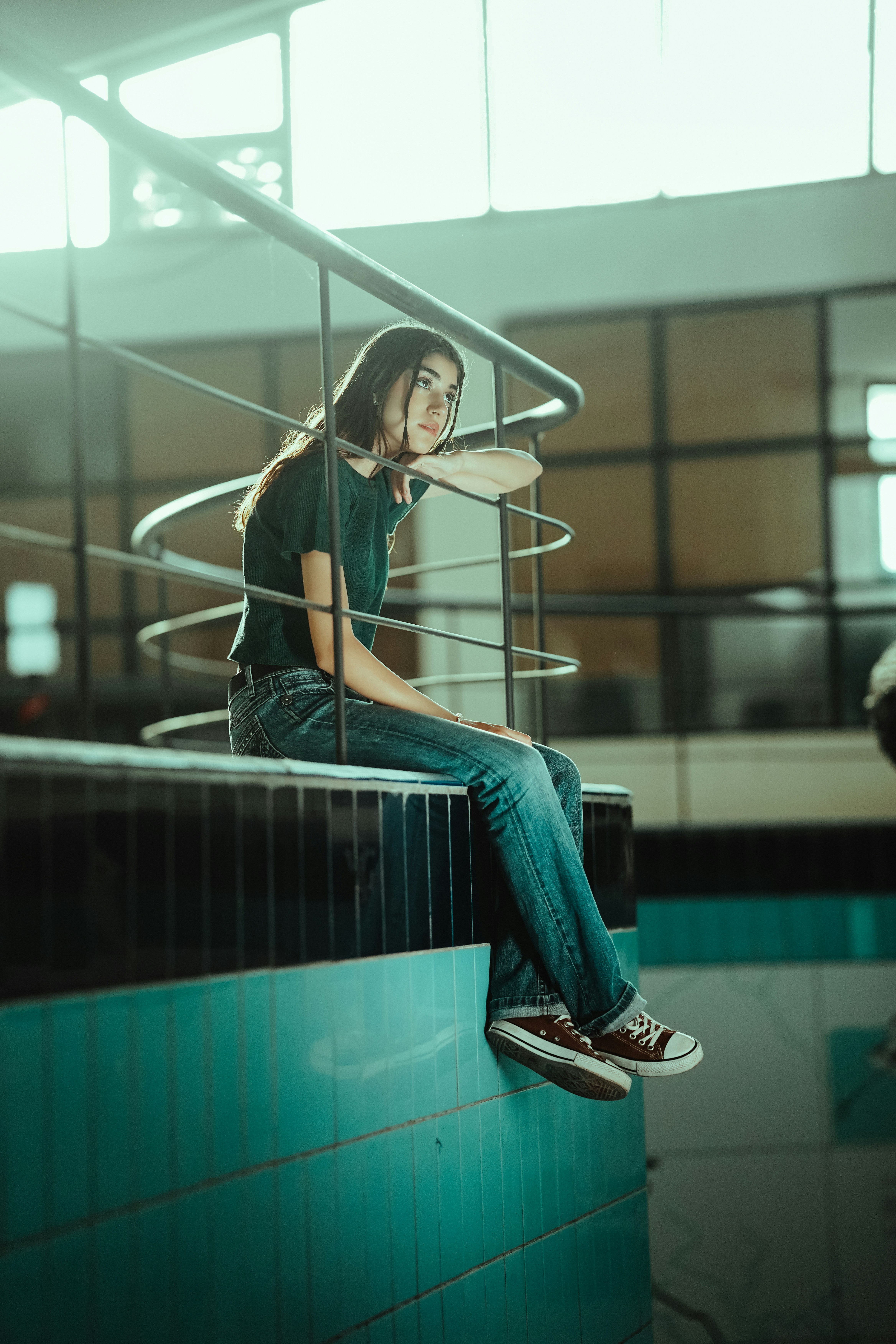 A person sitting on a stair rail in a building photo – Free Girl Image ...
