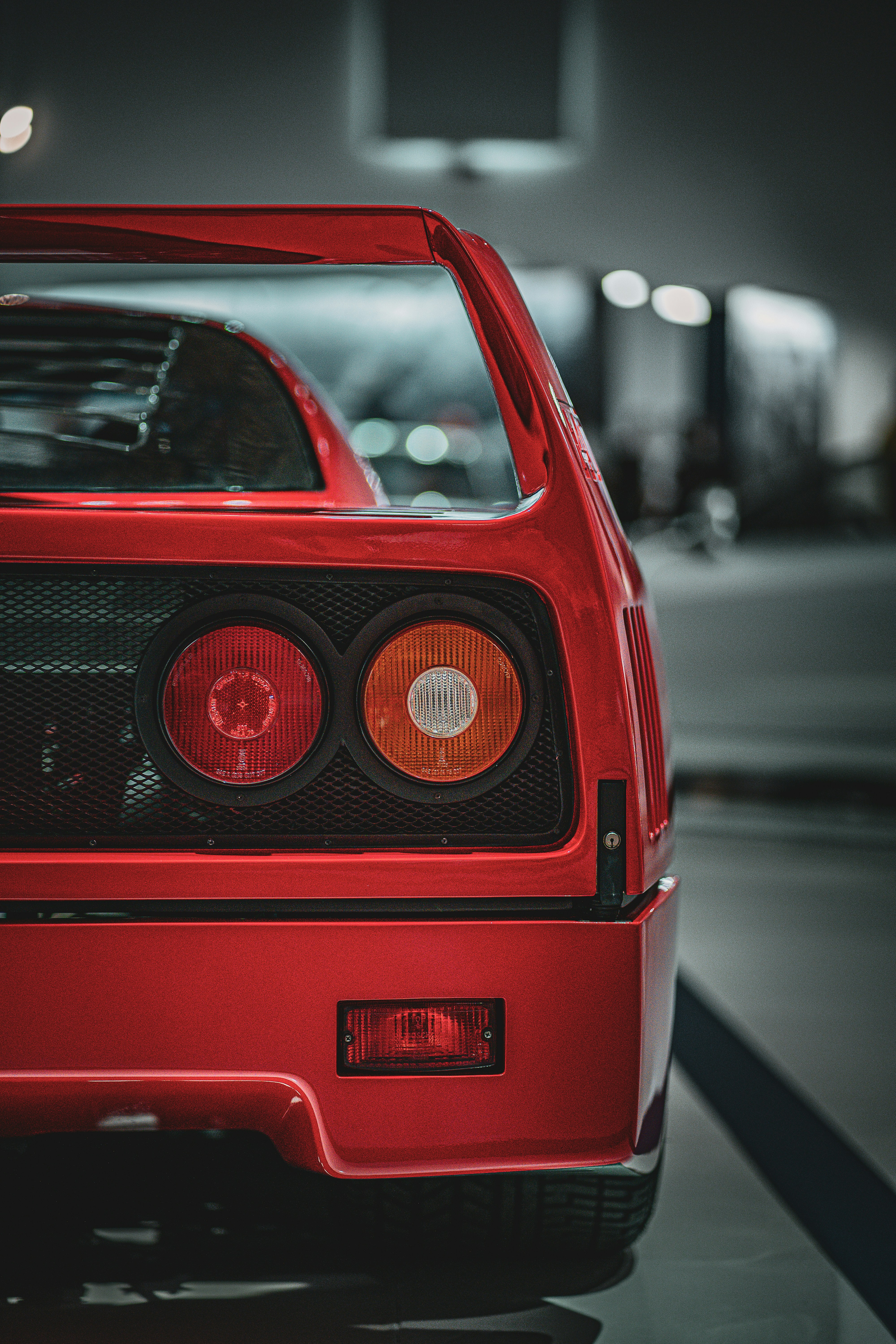 Close-up of a classic red sports car's rear end, showcasing its distinctive tail lights and sleek design elements.