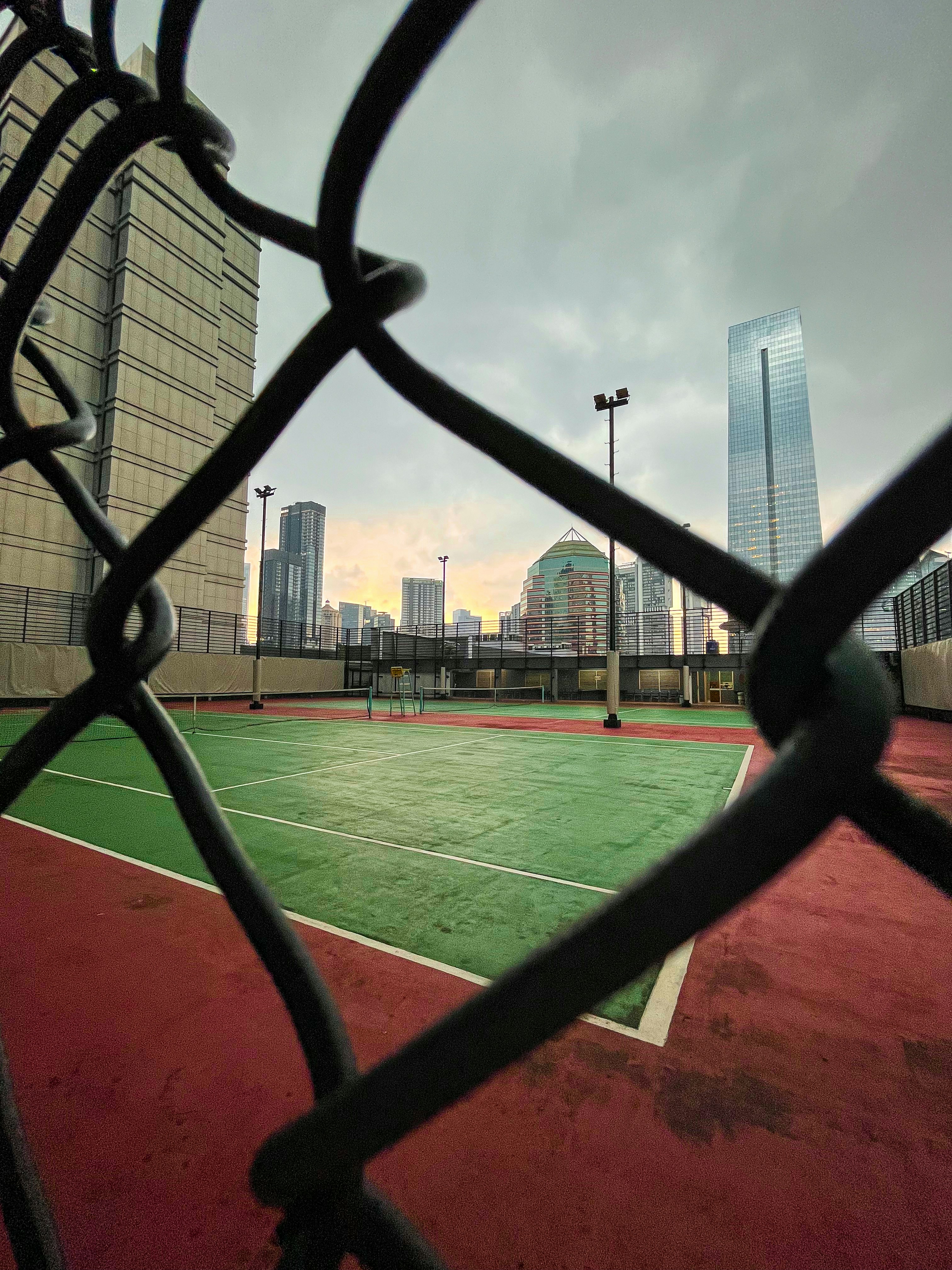 Through the Fence: Rooftop Court Framing a Modern Skyline at Dusk