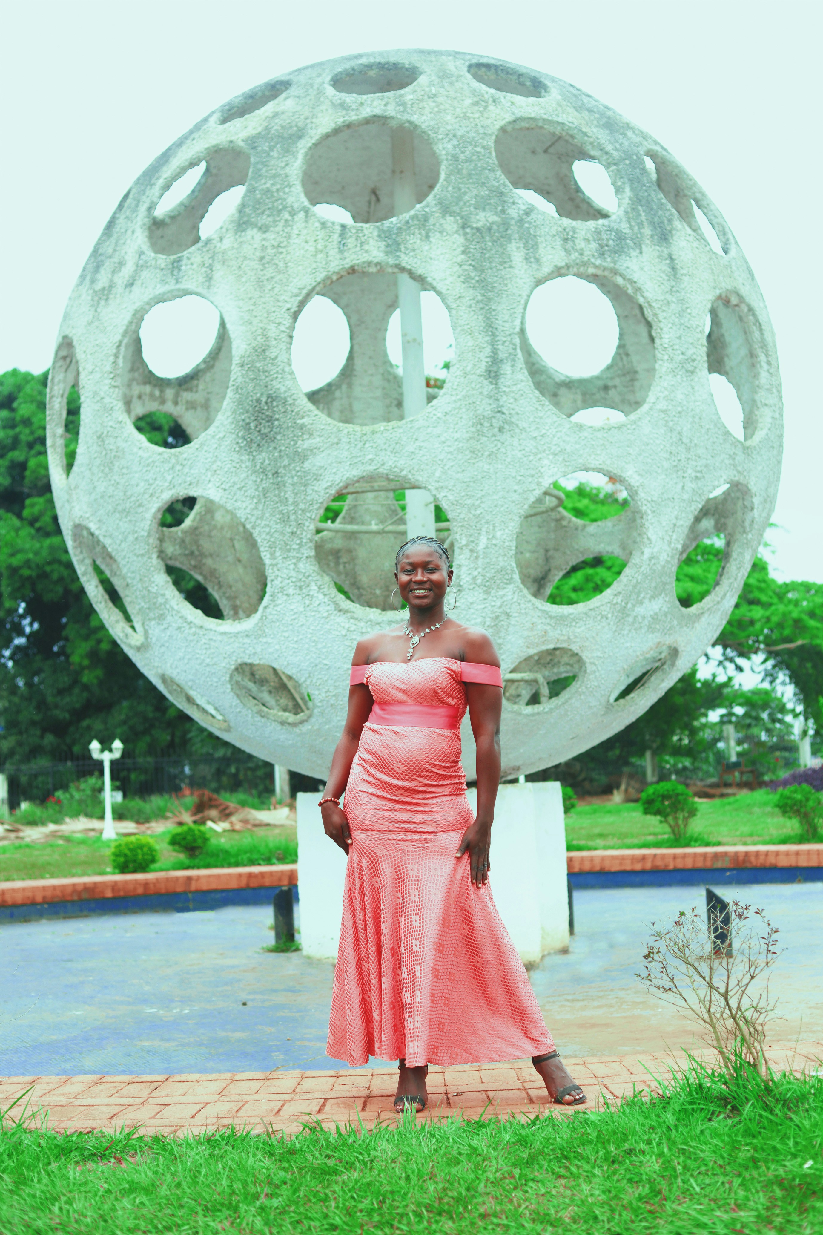 Lunar Sphere Portrait: Coral Gown Before a Geometric Monument