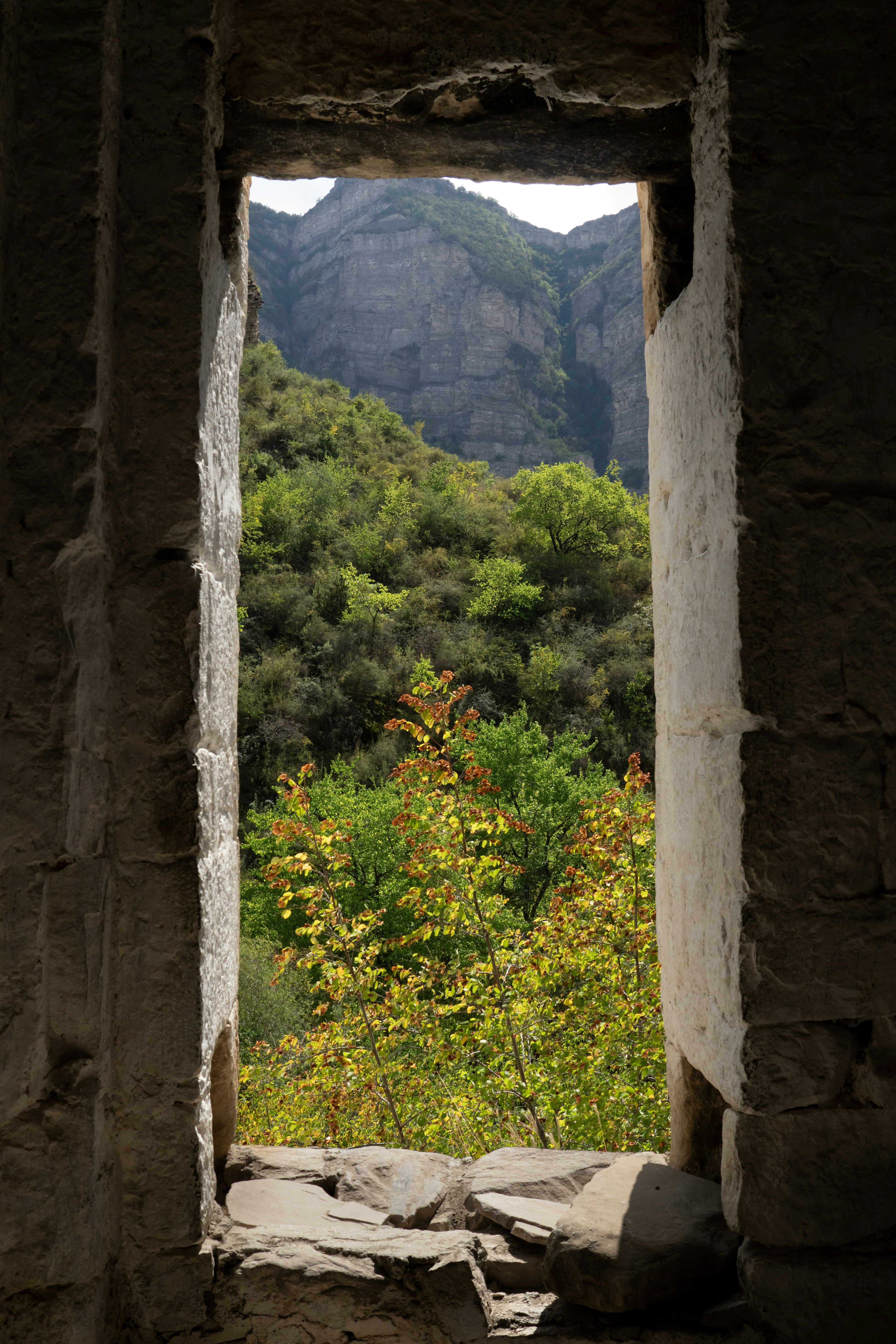 A window in a stone building with a view of mountains