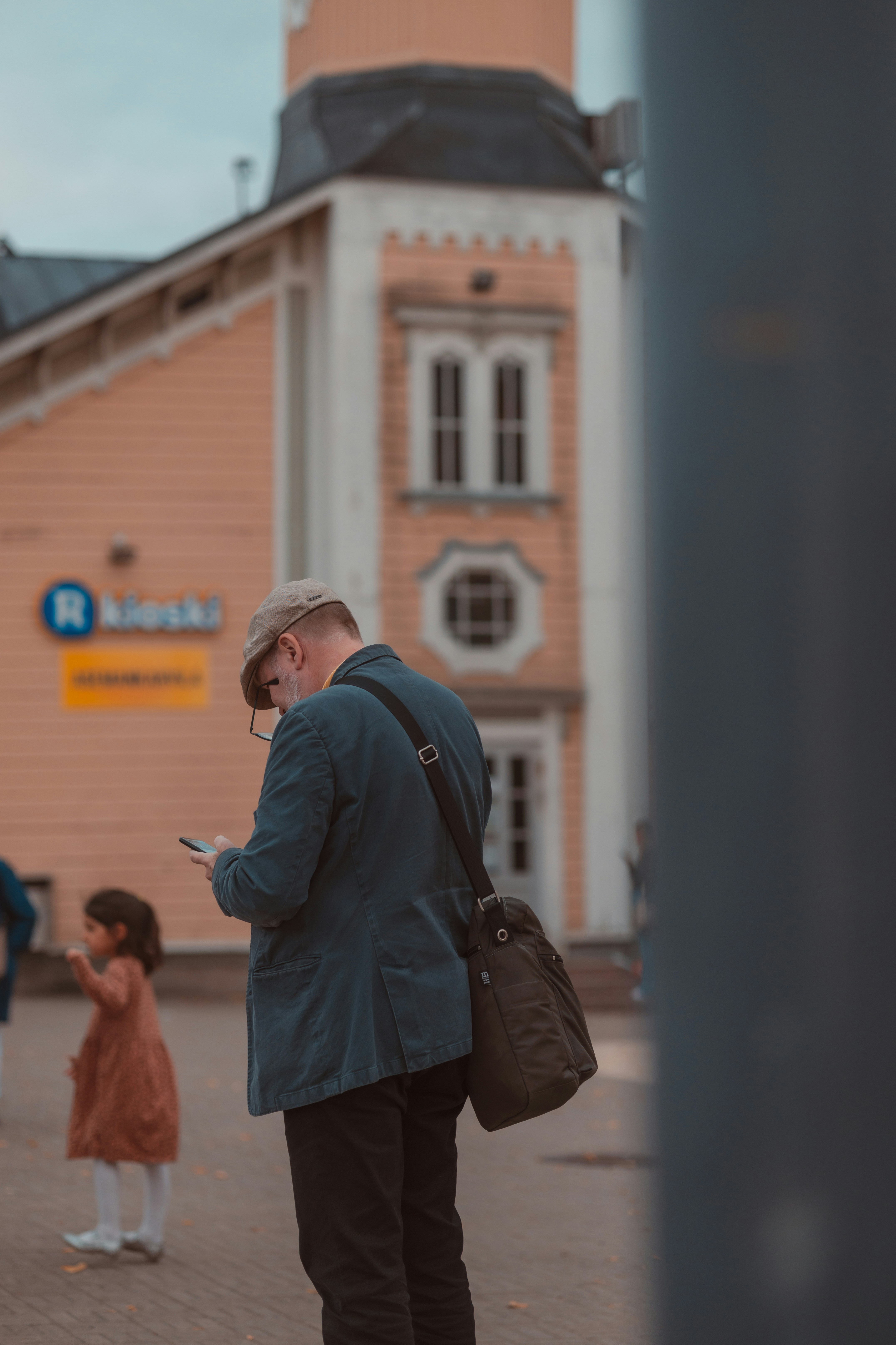 Between Peach Facades, a Man Checks His Phone